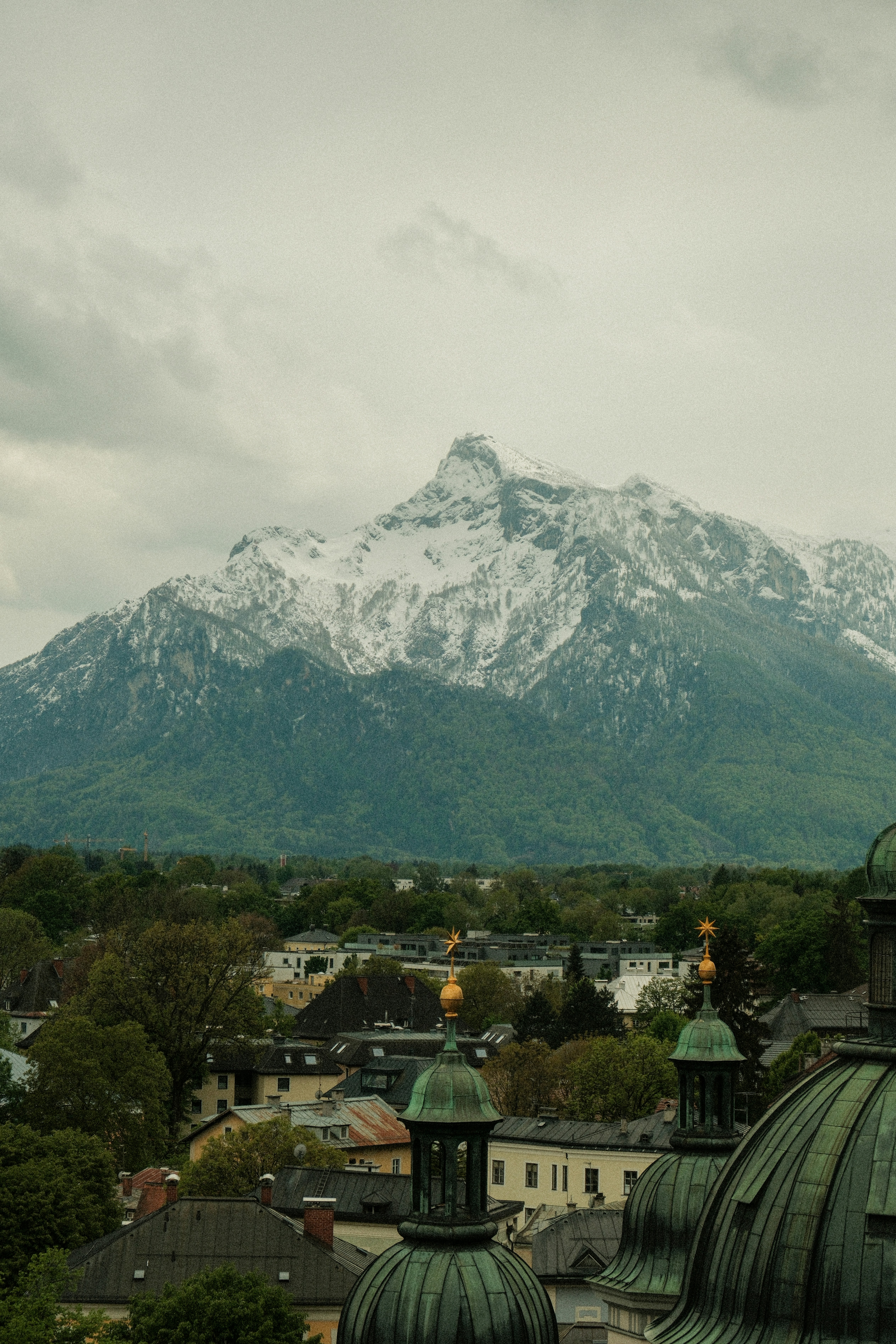 Snowbound Crest Over a Green-Domed Cityscape