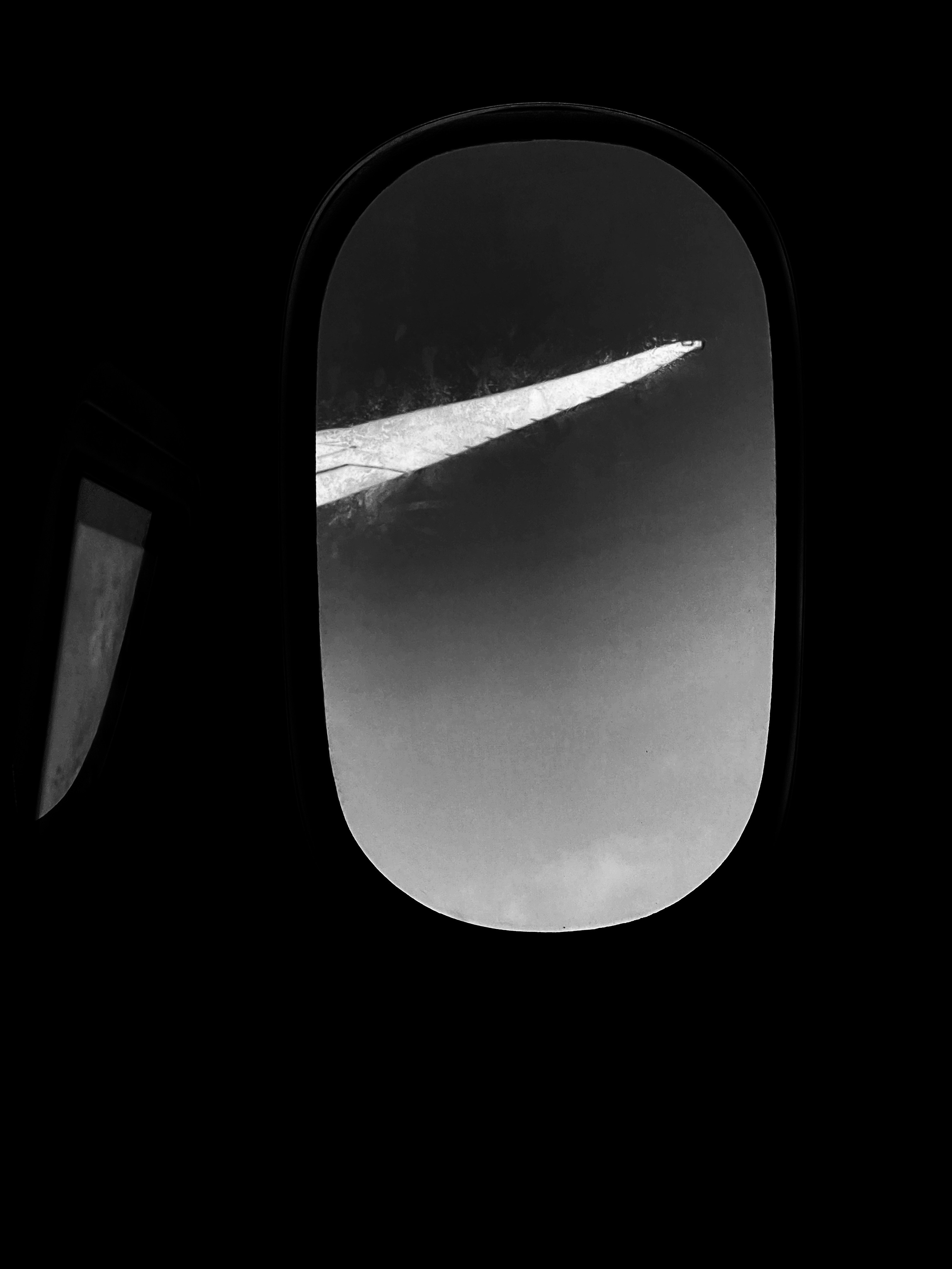 Wing Slice Through a Monochrome Dusk from a Passenger Window
