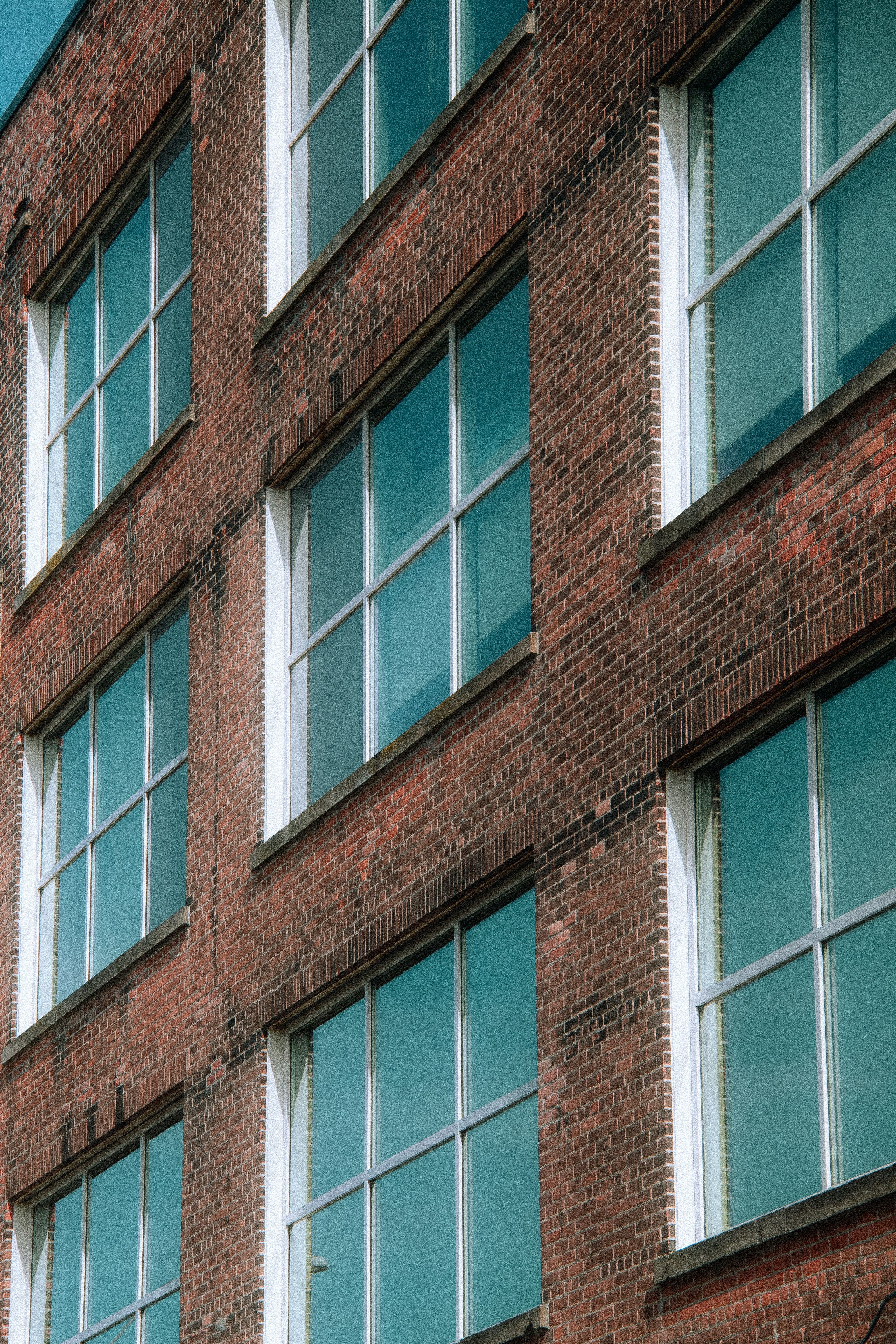 A red brick building with many windows and a clock photo – Free ...