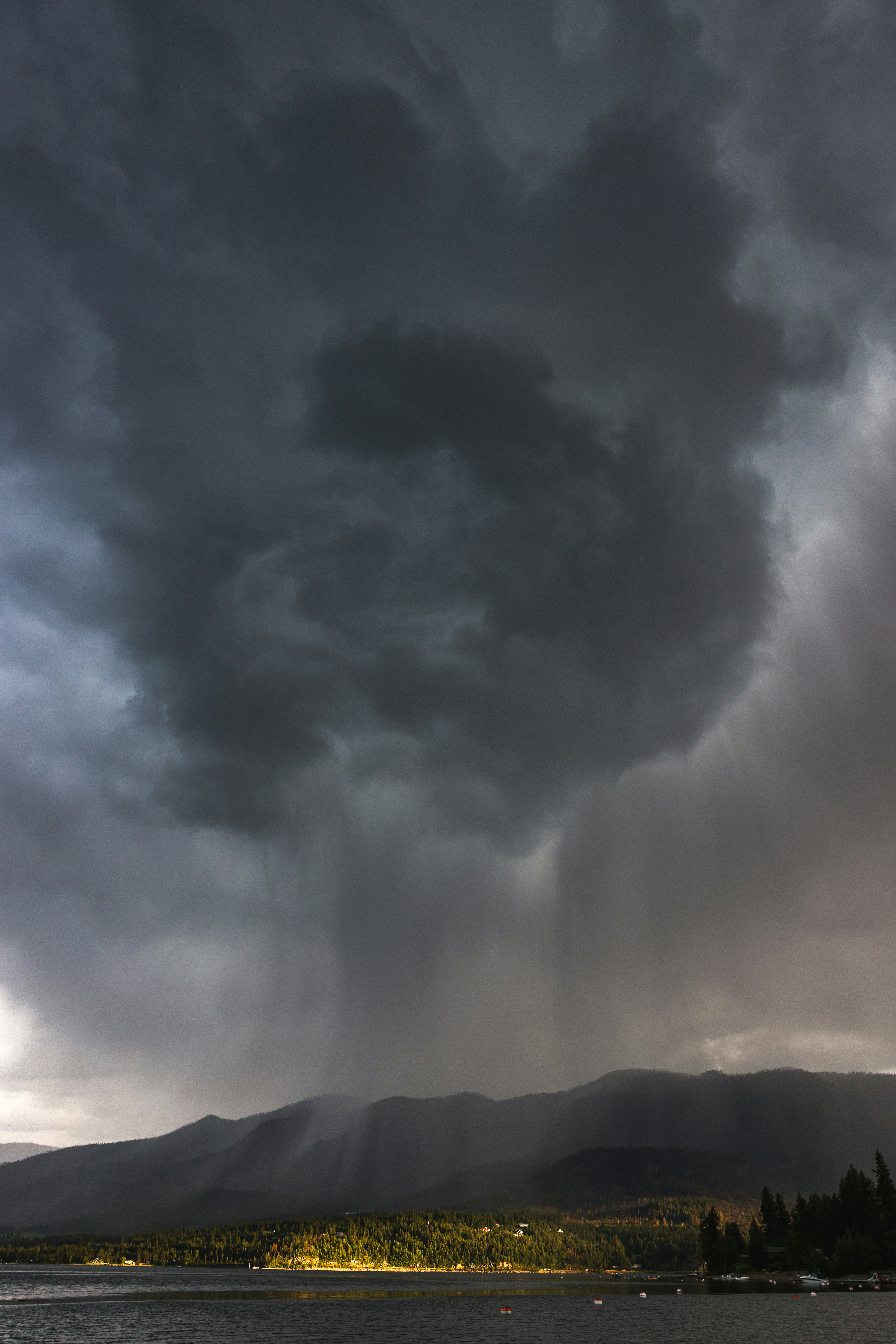 A large storm moving over a lake with mountains in the background photo ...