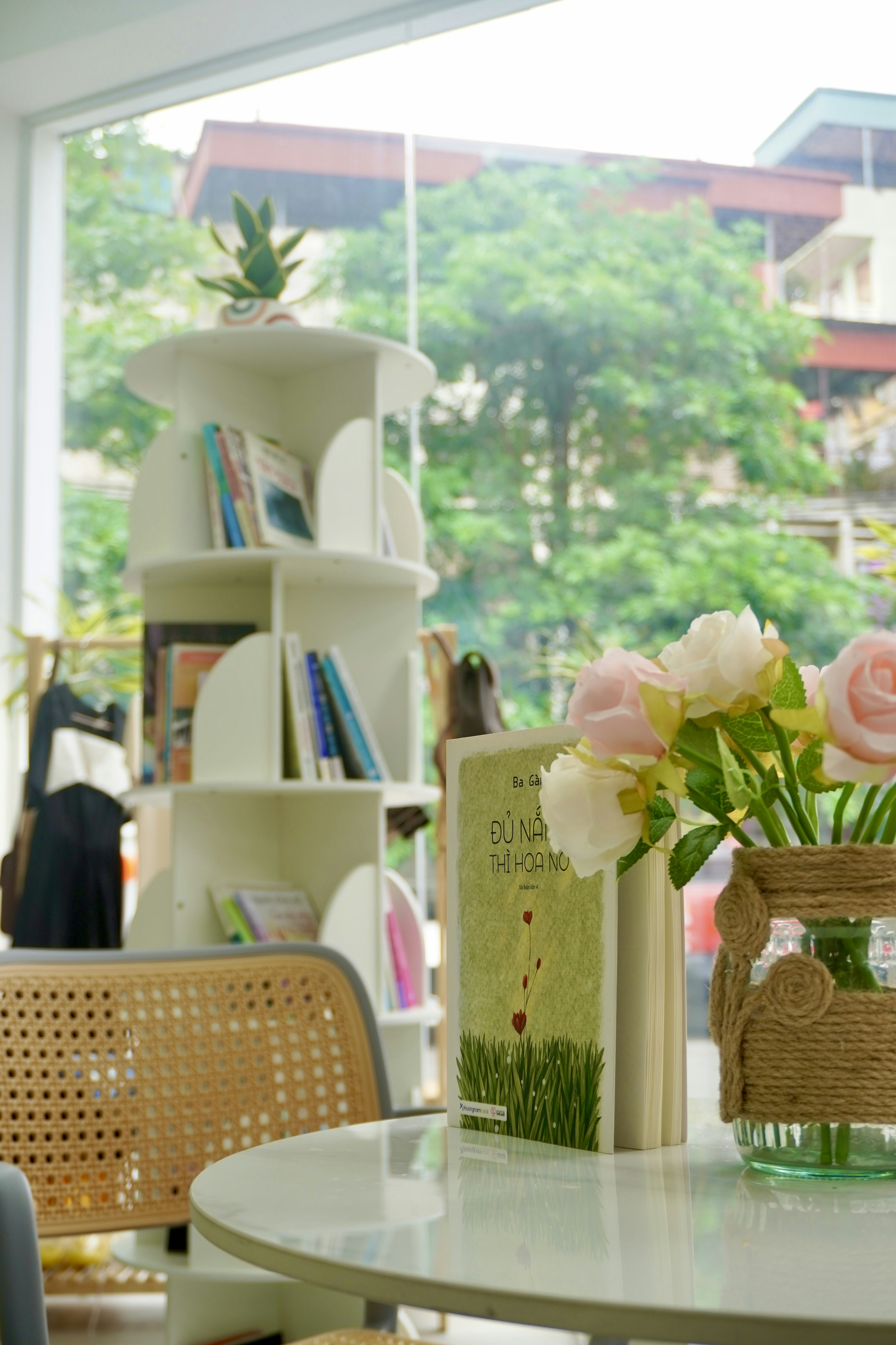 Daylight Café Nook: Circular white shelf, glass table, and a bouquet by the window