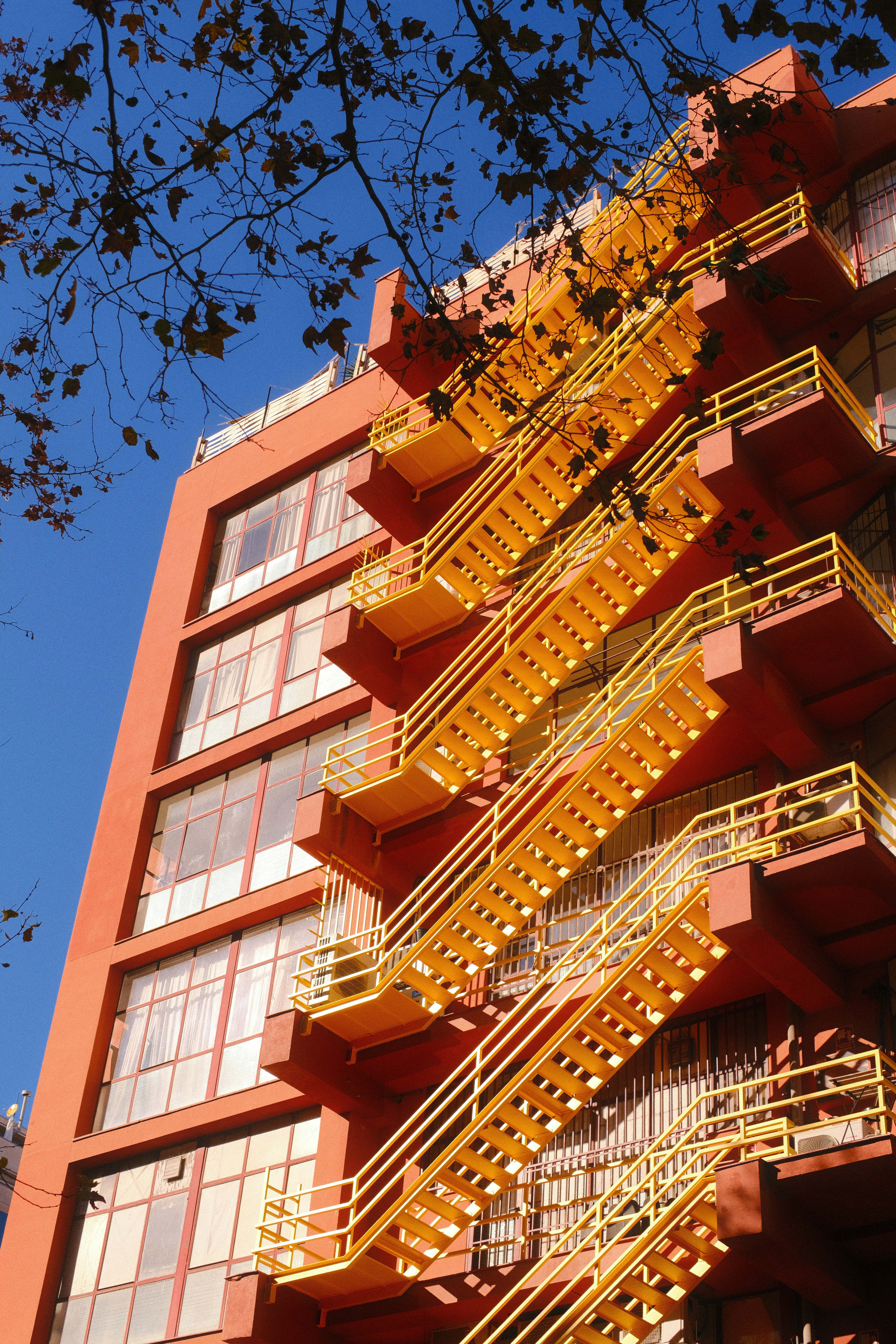 Crimson Fire Escape Cuts Through a Sapphire Sky