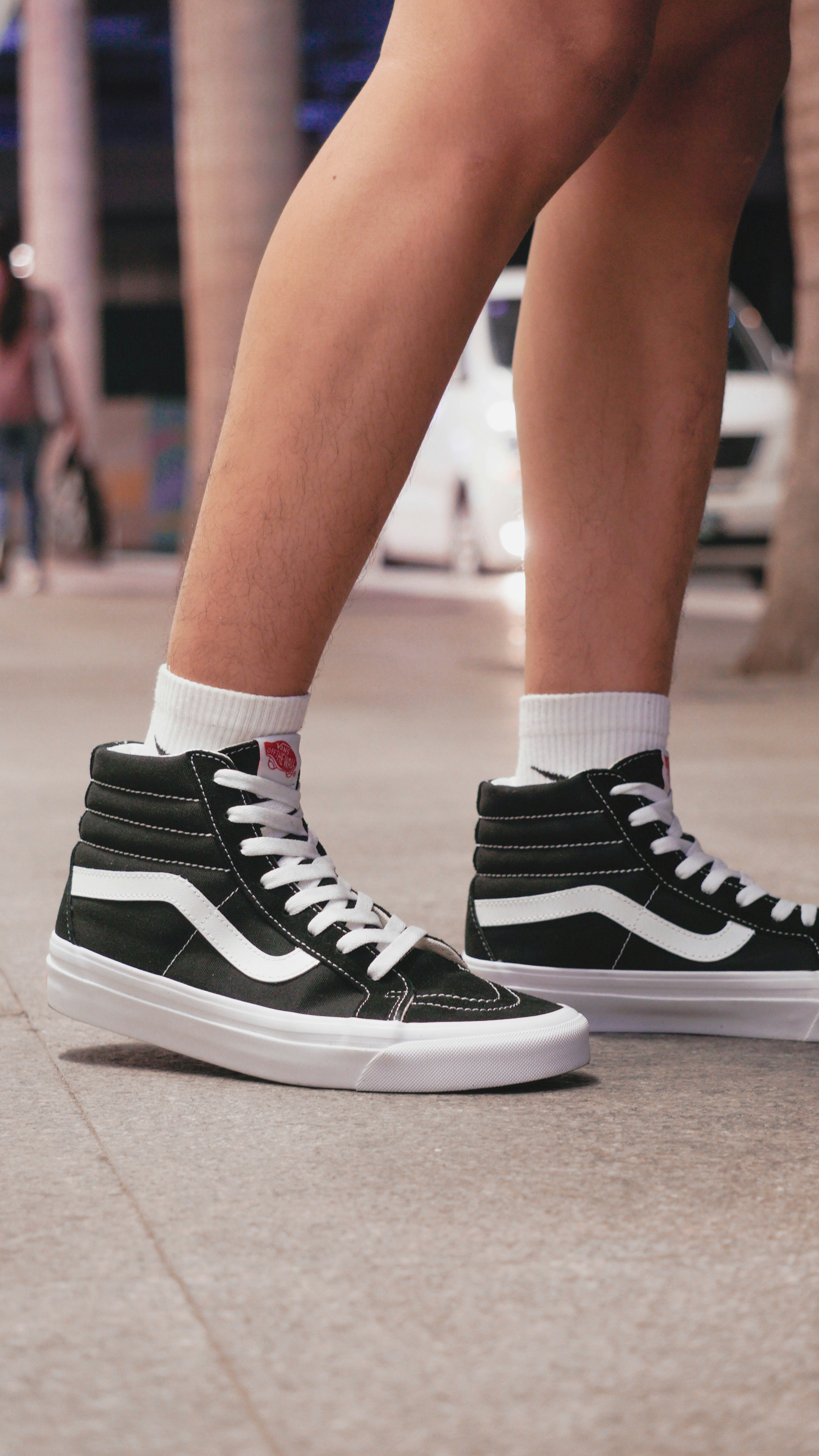 High-top sneakers prominently displayed against an urban backdrop, highlighting street fashion trends. The scene captures the essence of casual style in a lively environment.