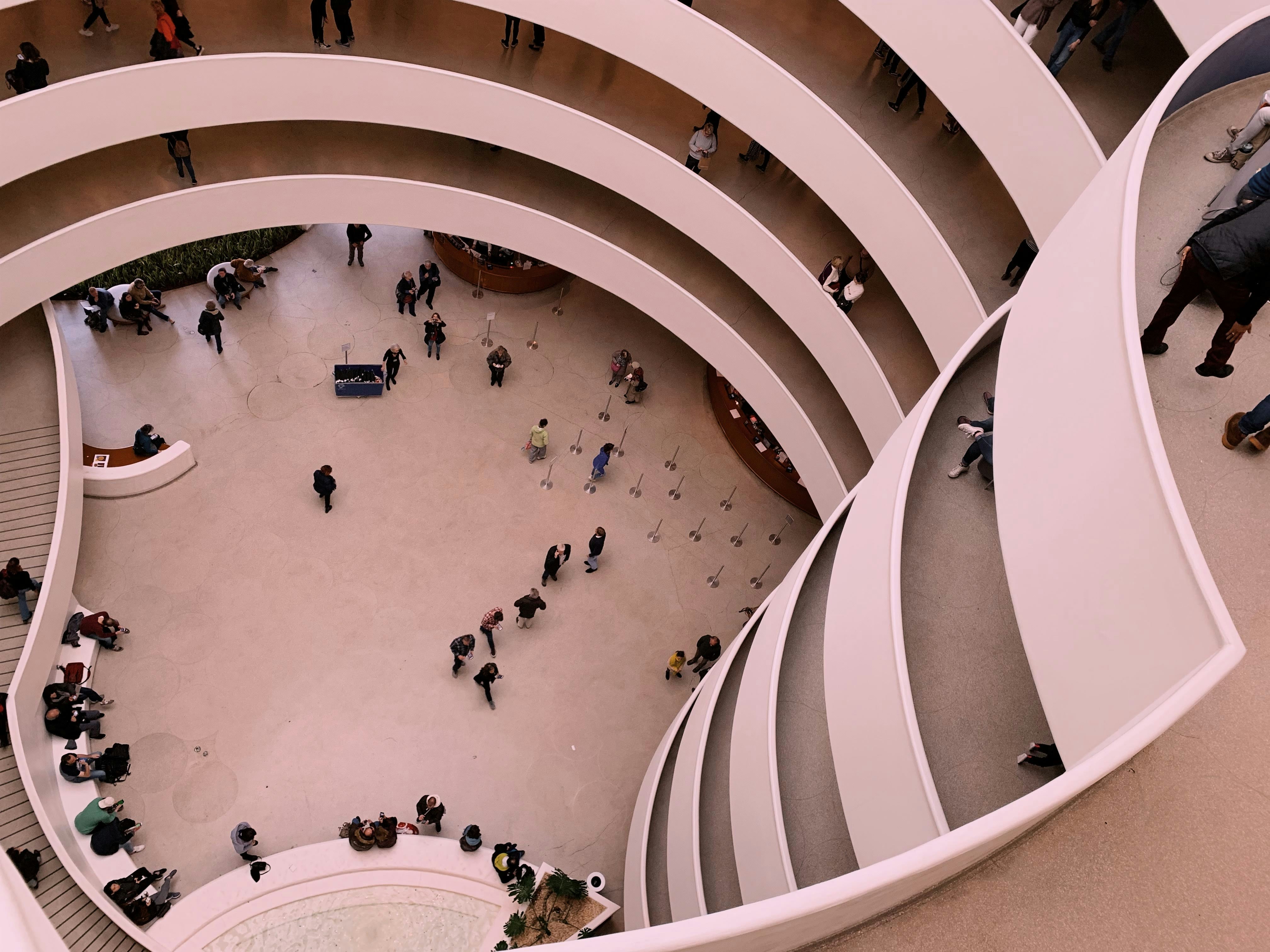 A group of people walking around a building photo – Free Art Image on ...