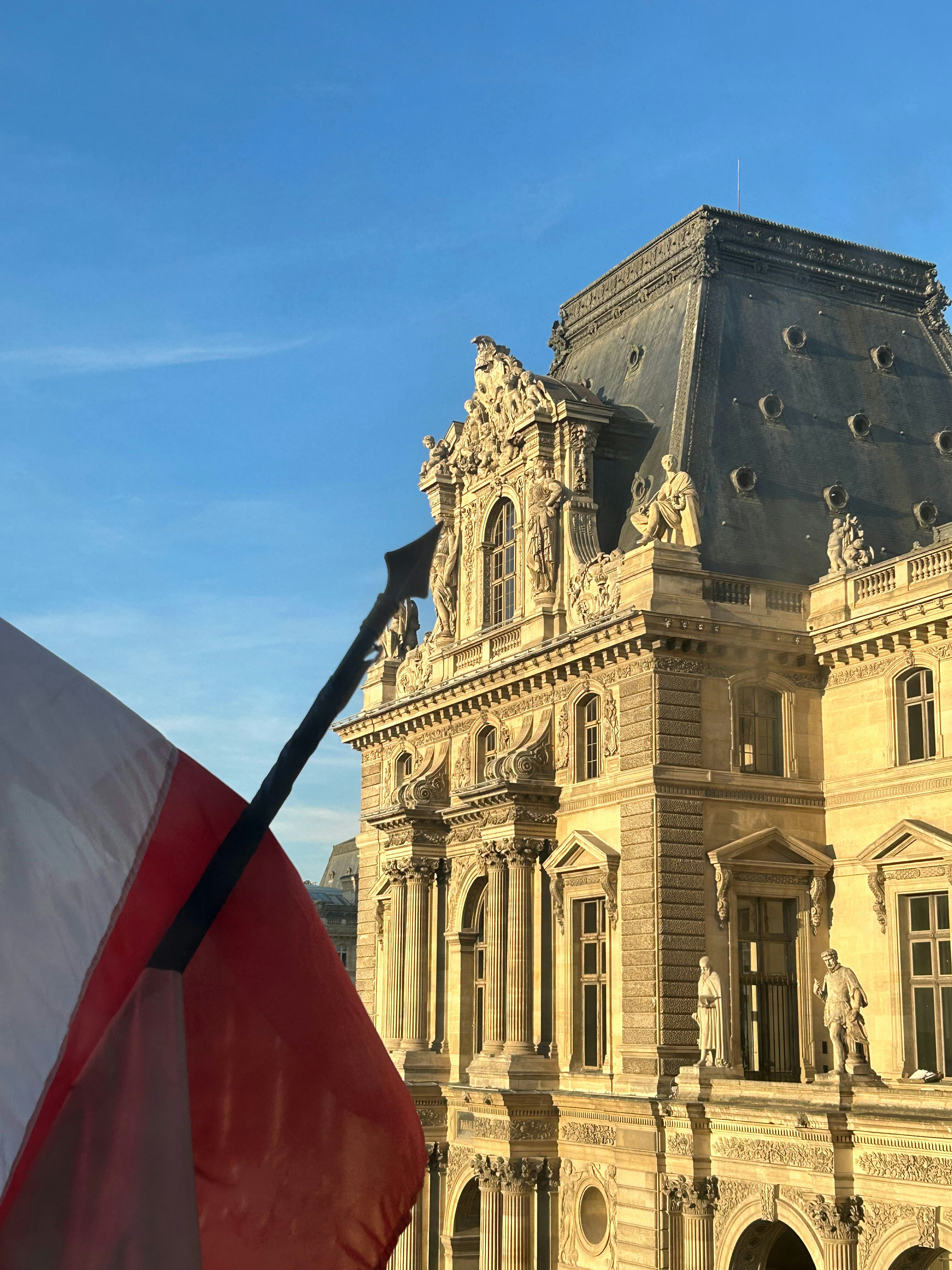 Beaux-Arts Majesty: Sunlit Facade Framed by a Foreground Flag