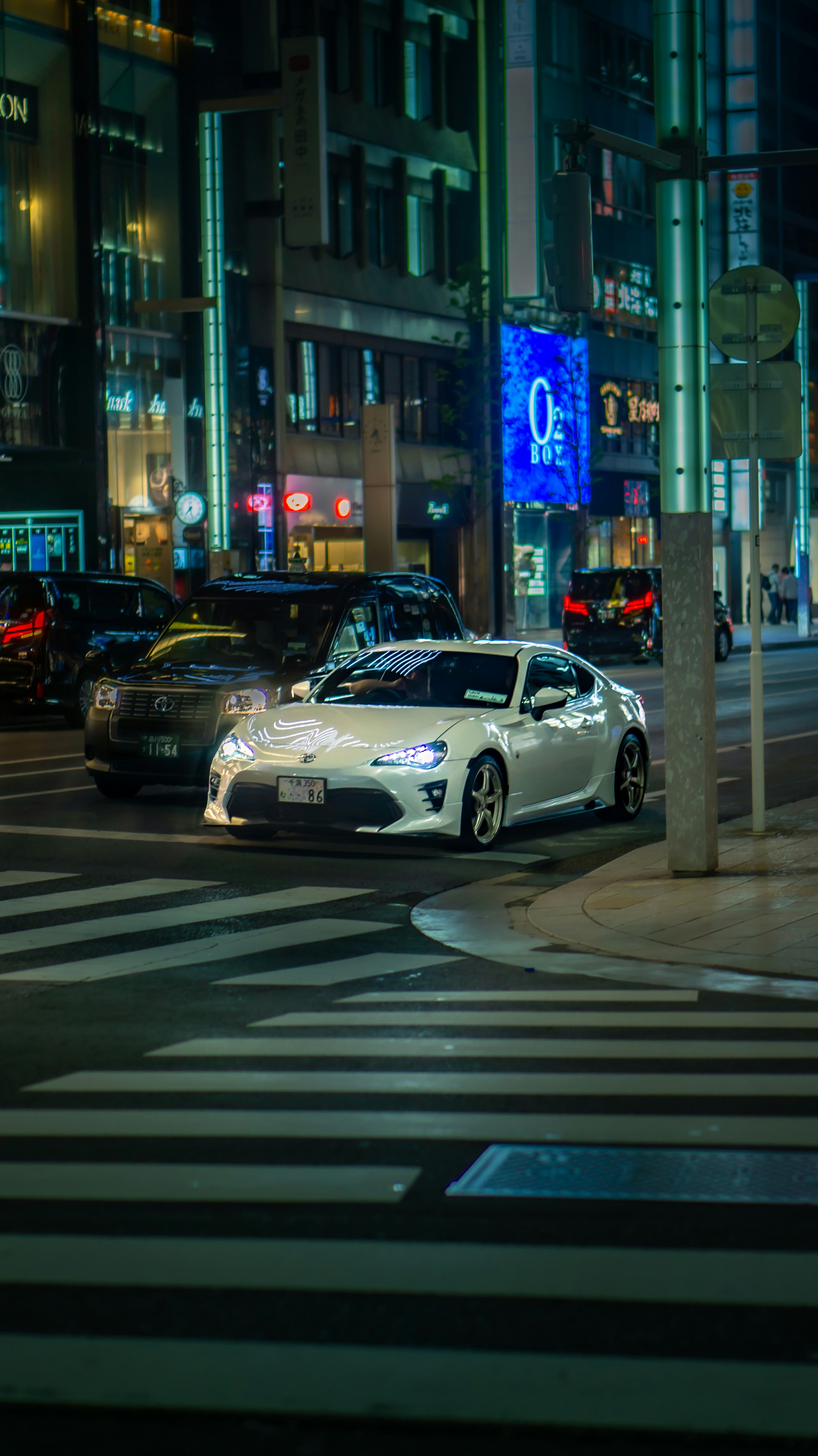 Neon Crosswalk Pulse: White sports coupe under a night-city glow