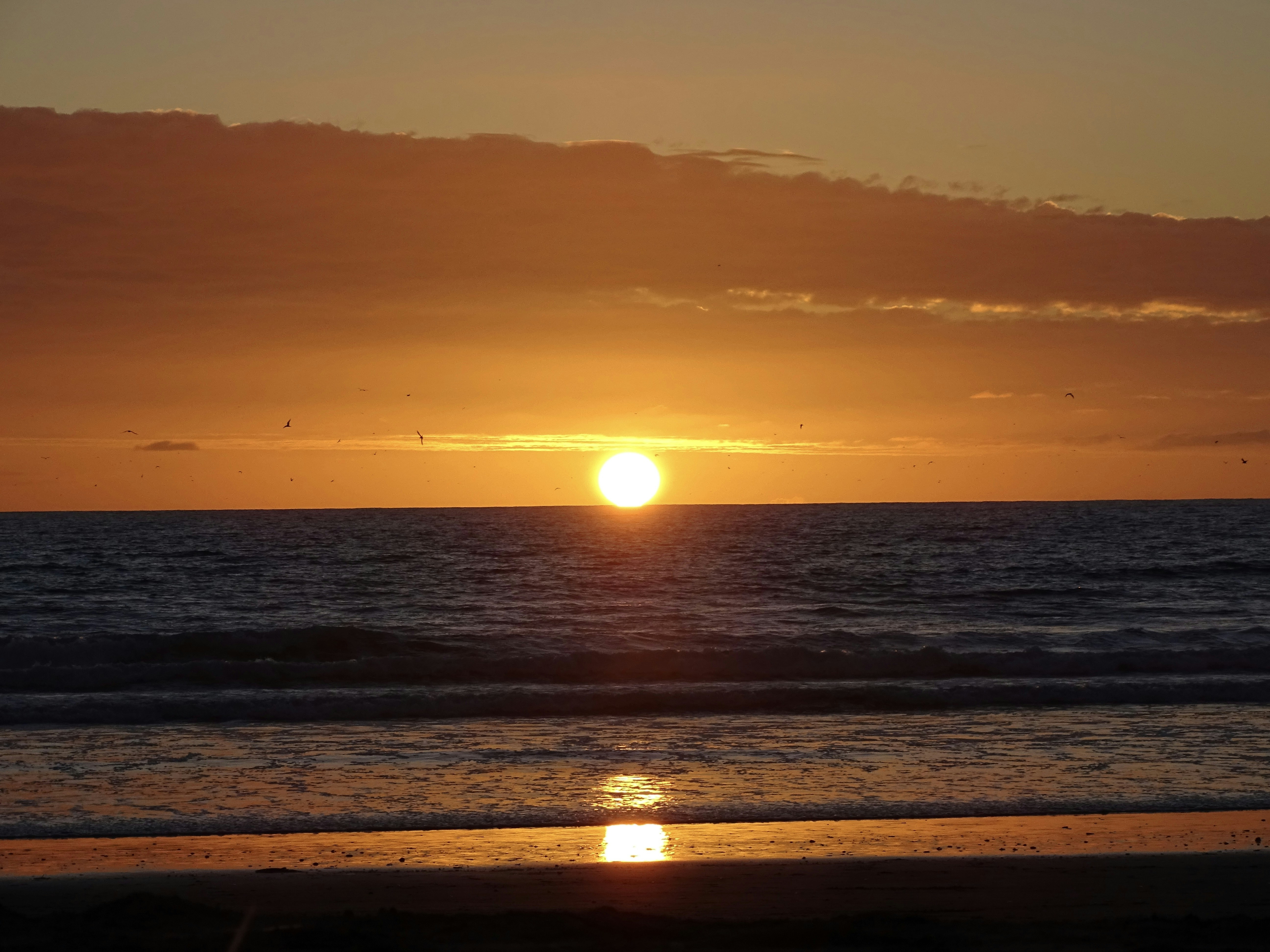 Sunset over the ocean with vibrant orange and yellow hues reflecting on the water.