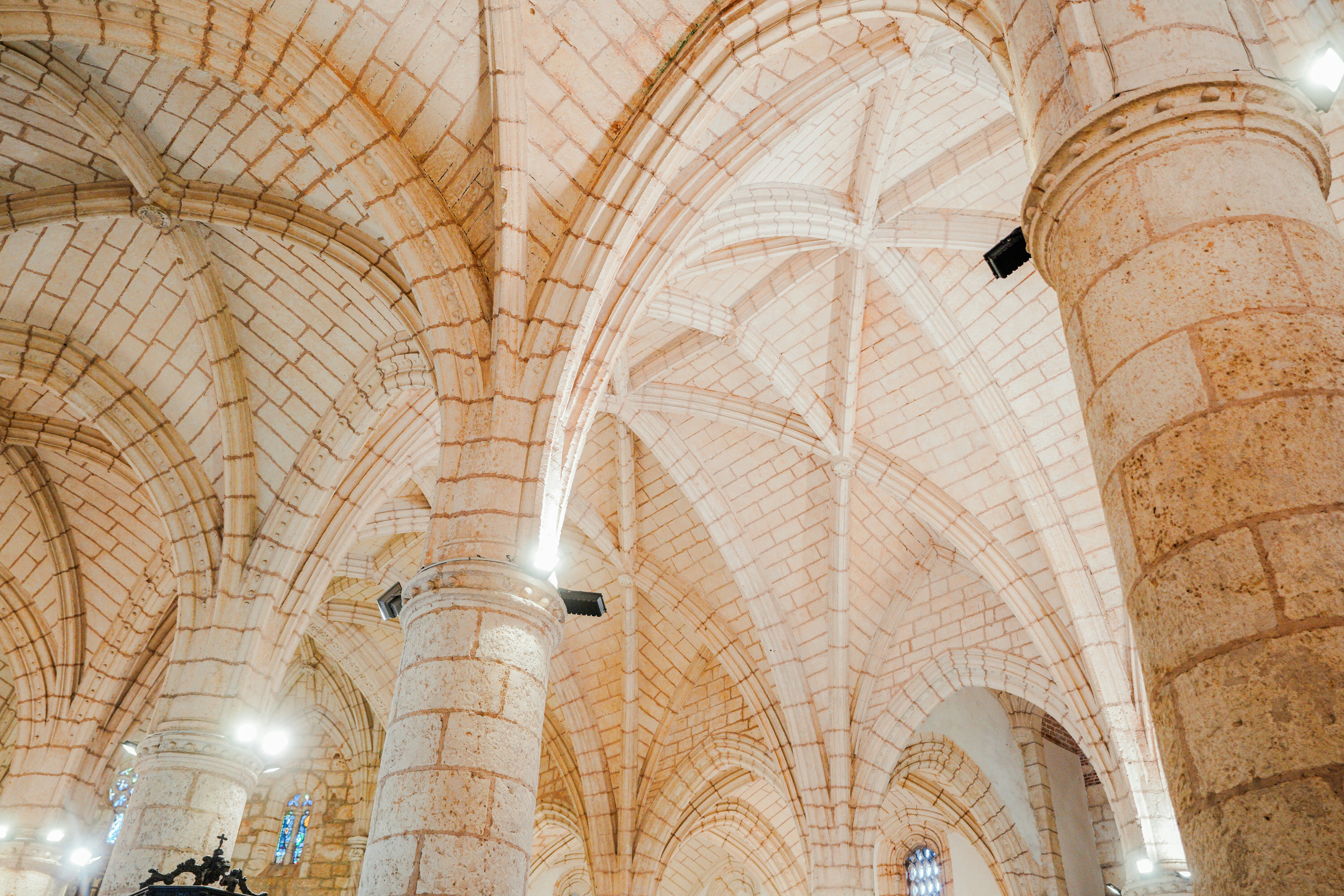 High vaulted ceilings and massive stone columns in a cathedral interior, with soft lighting enhancing architectural details.