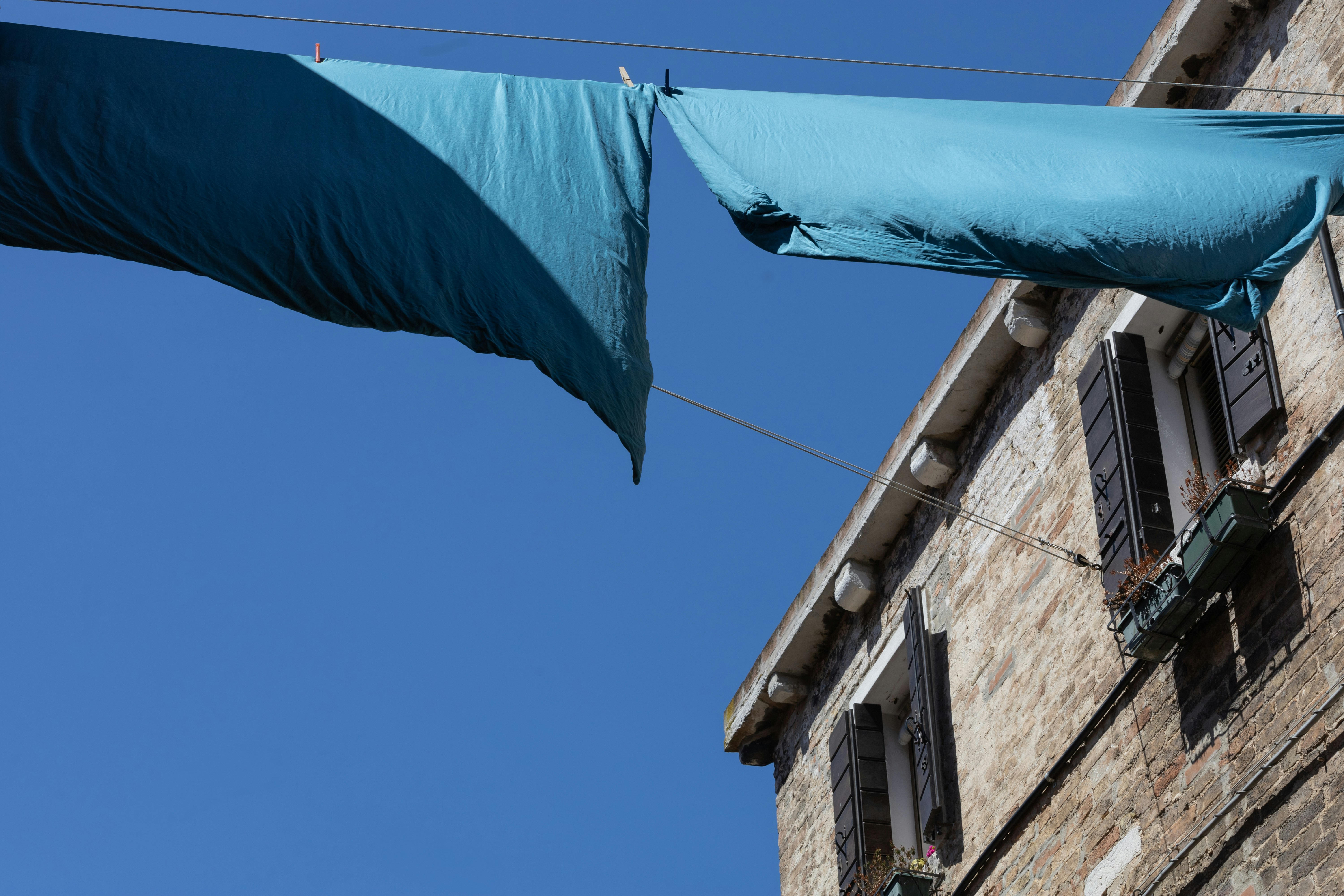 A blue tarp hanging from a clothes line next to a brick building photo ...
