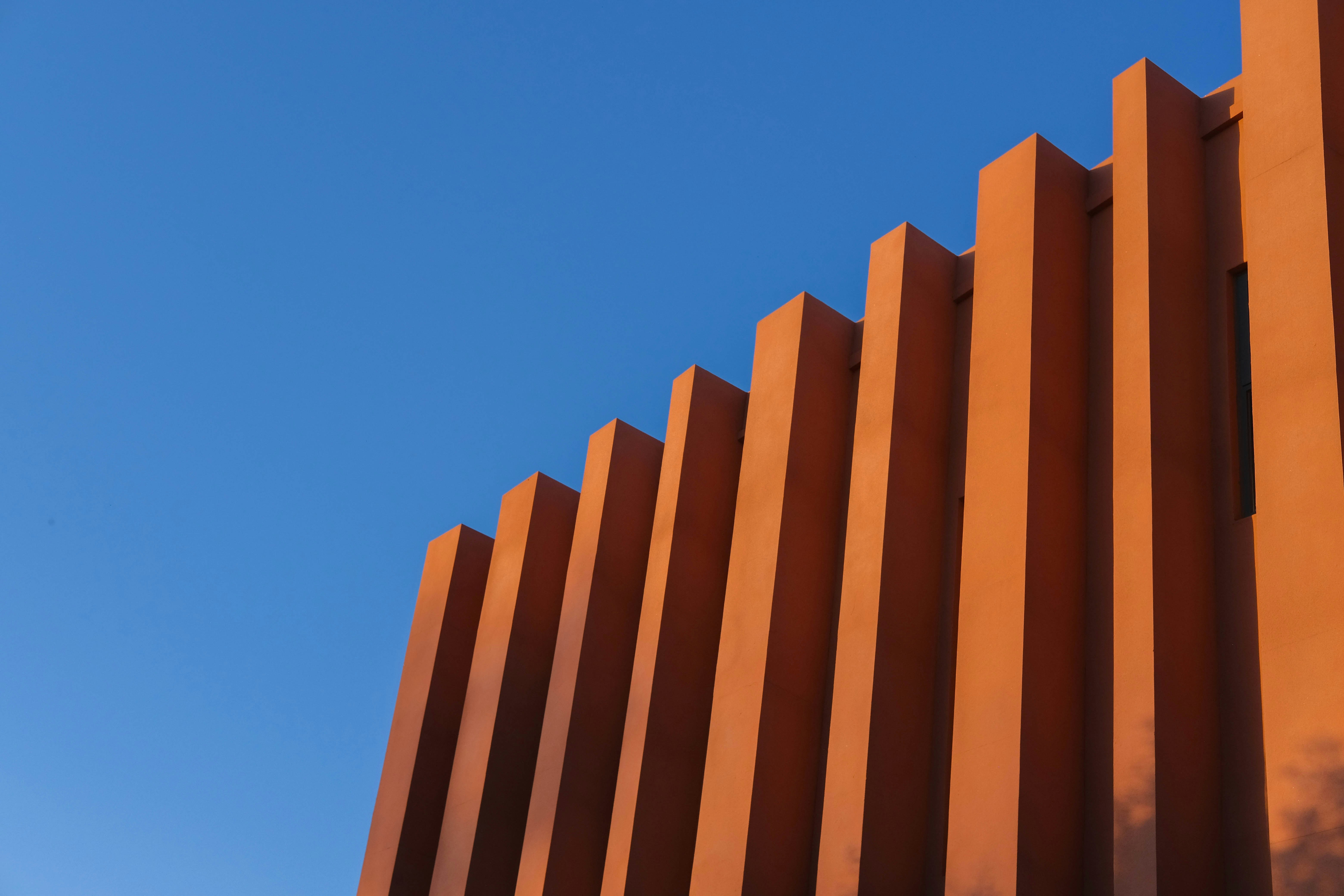 A tall orange building with a blue sky in the background photo – Free ...