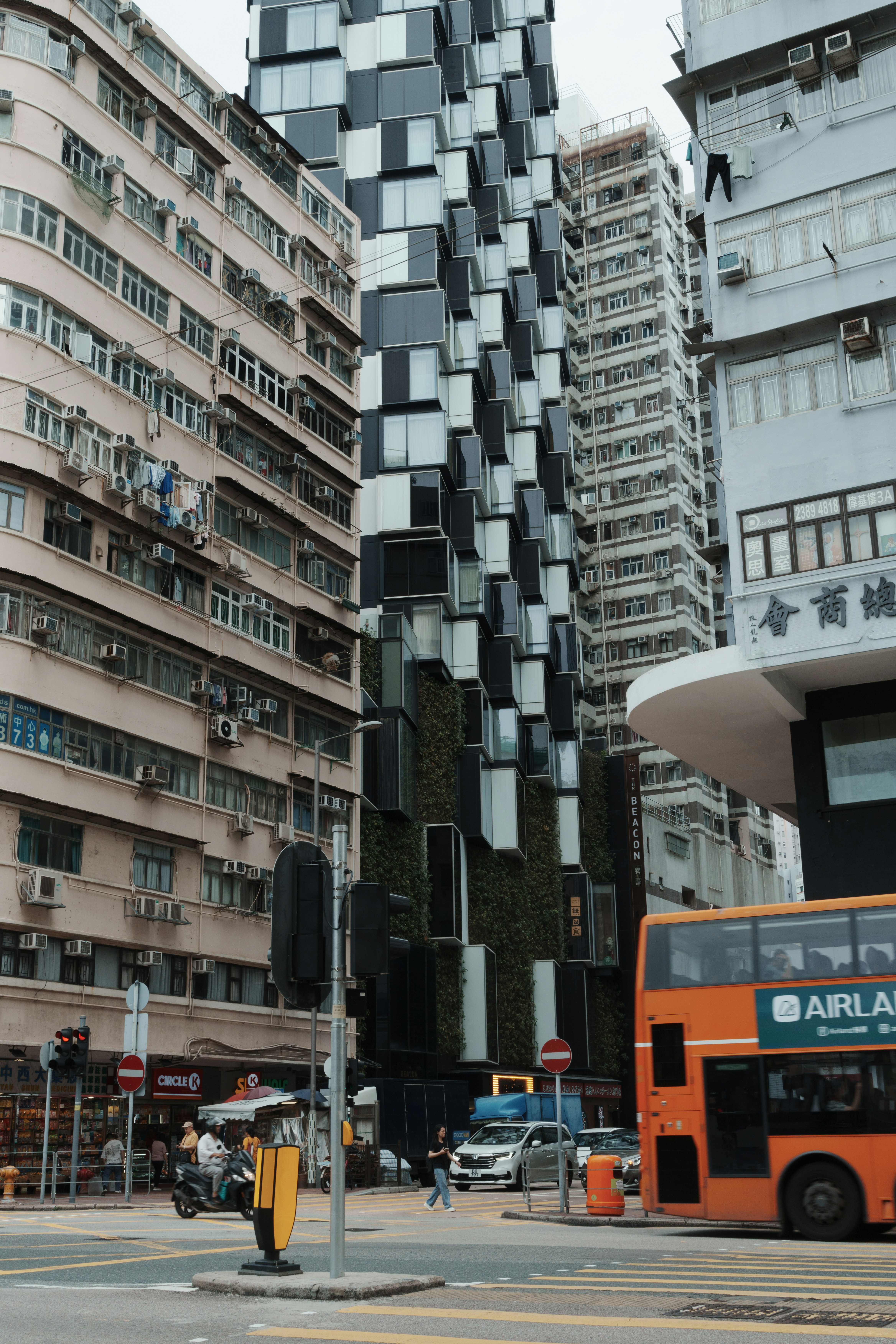 Urban Prism: A Glass-Walled Tower Framed by Concrete Facades and an Orange Double-Decker Bus