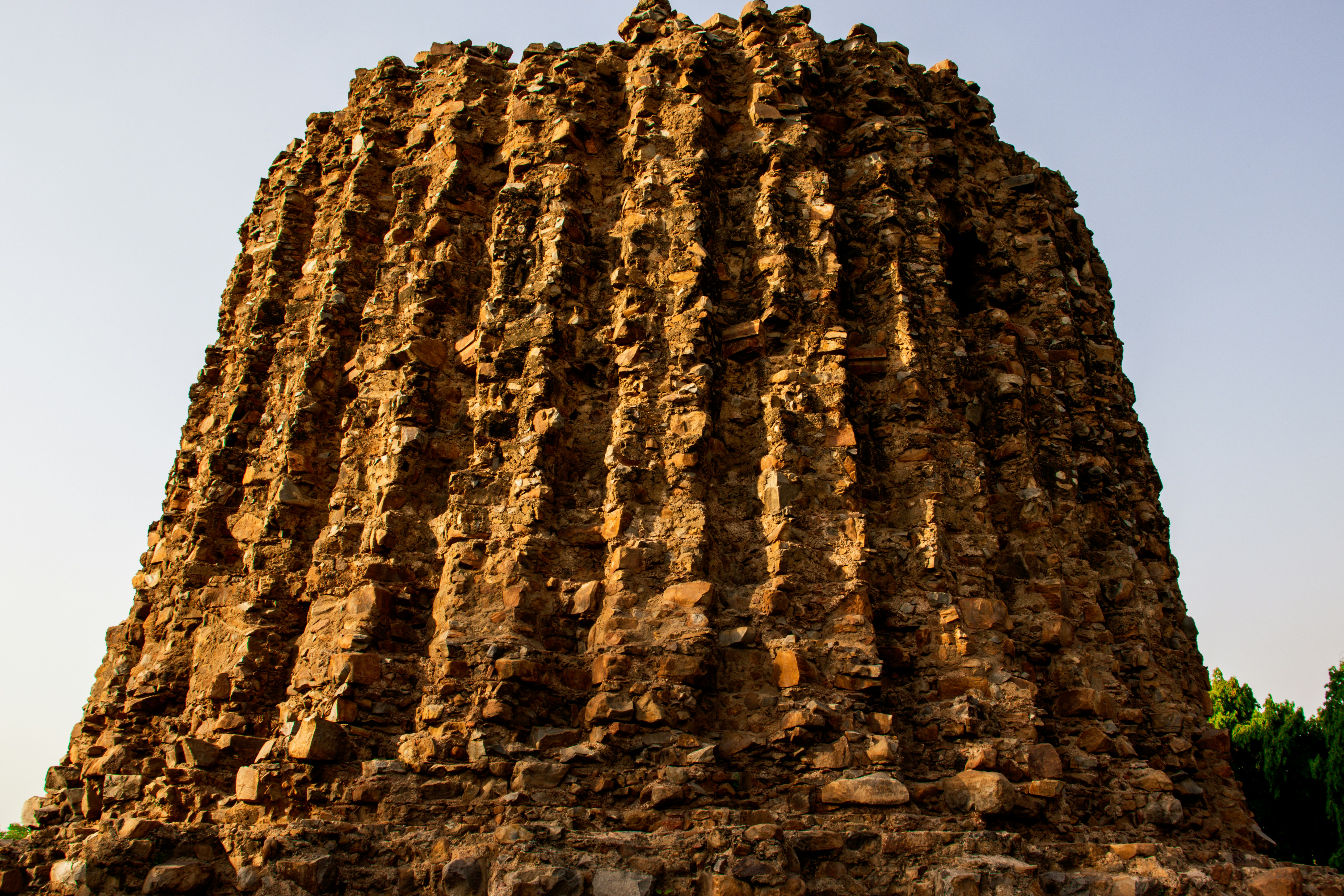 Sunlit Weathered Column: A Ribbed Stone Tower Reaching Toward a Pale Sky