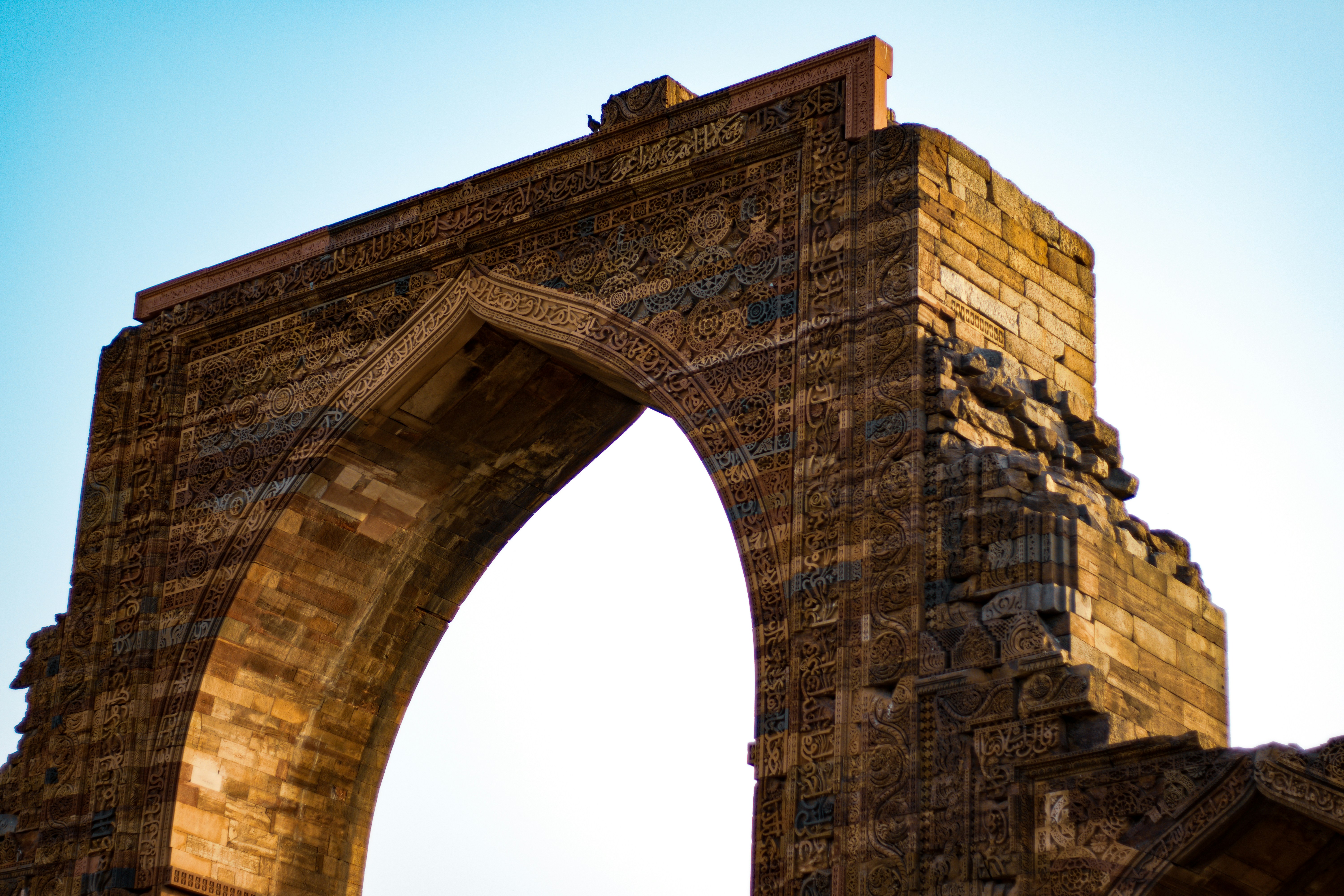 Weathered Arch Under a Clear Blue Sky: Stone Texture in Warm Light