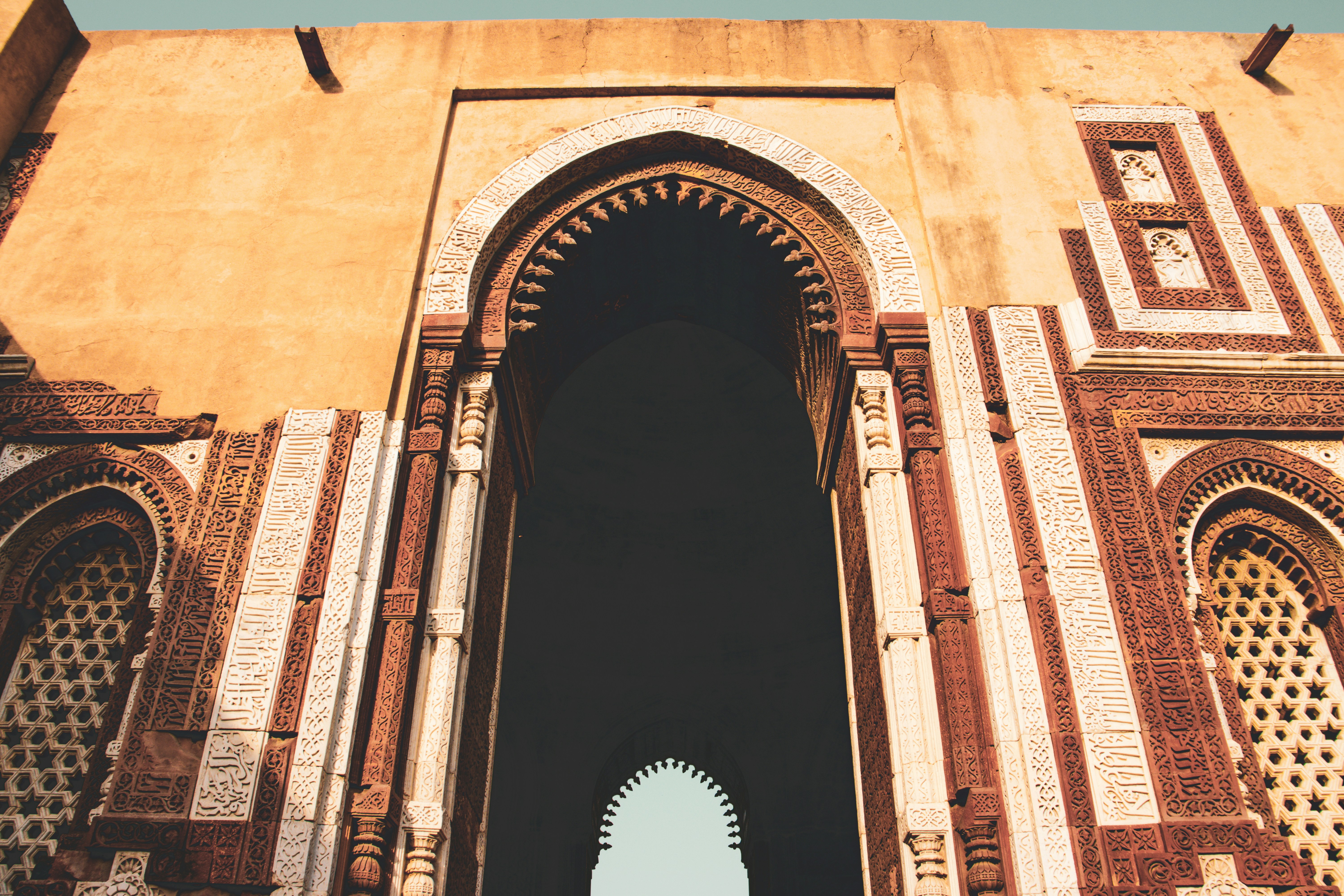 Crimson Archway: Intricate Moorish Brickwork Framing a Shadowed Portal
