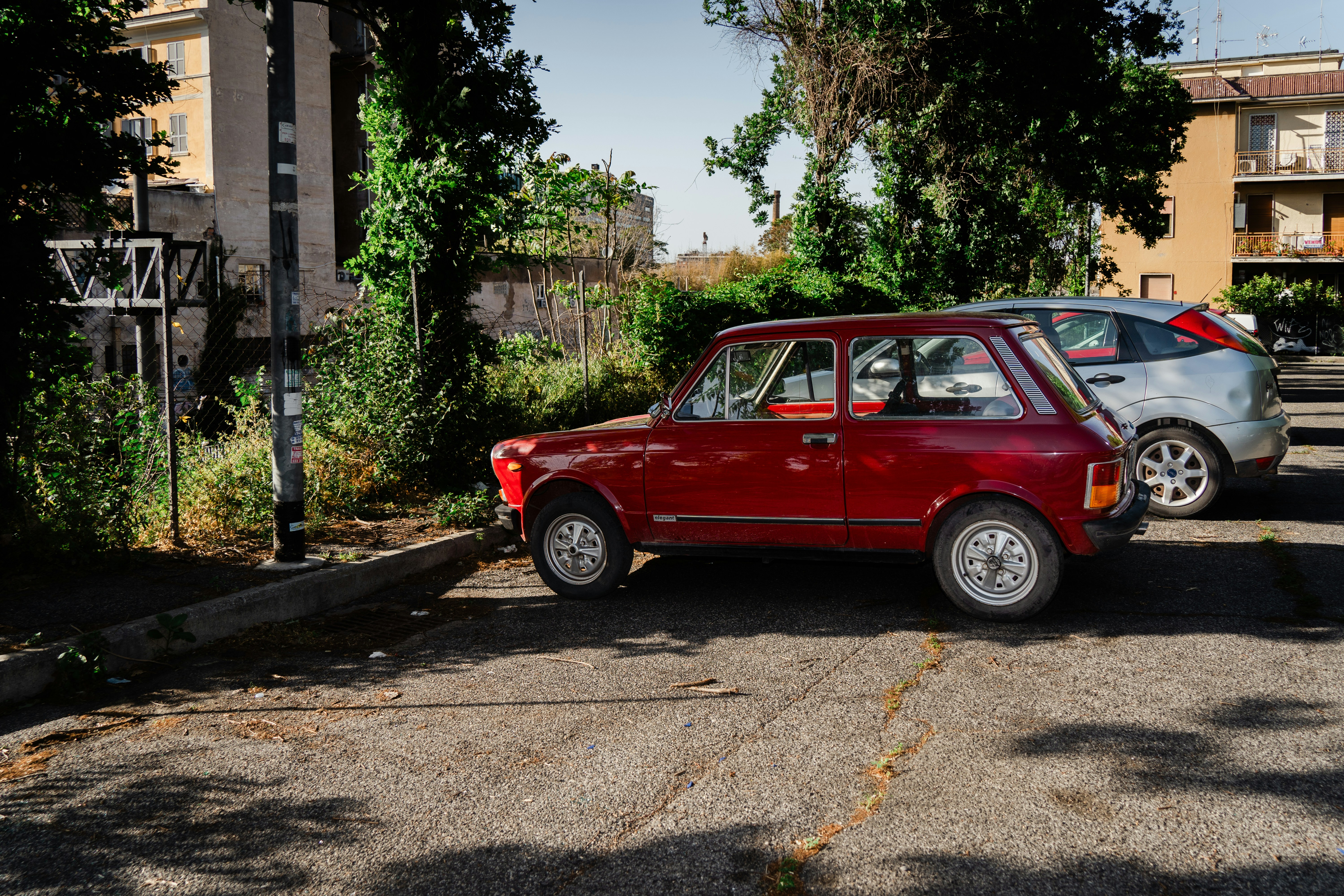 Sunlit Vintage Red Sedan in a Quiet Urban Parking Lot