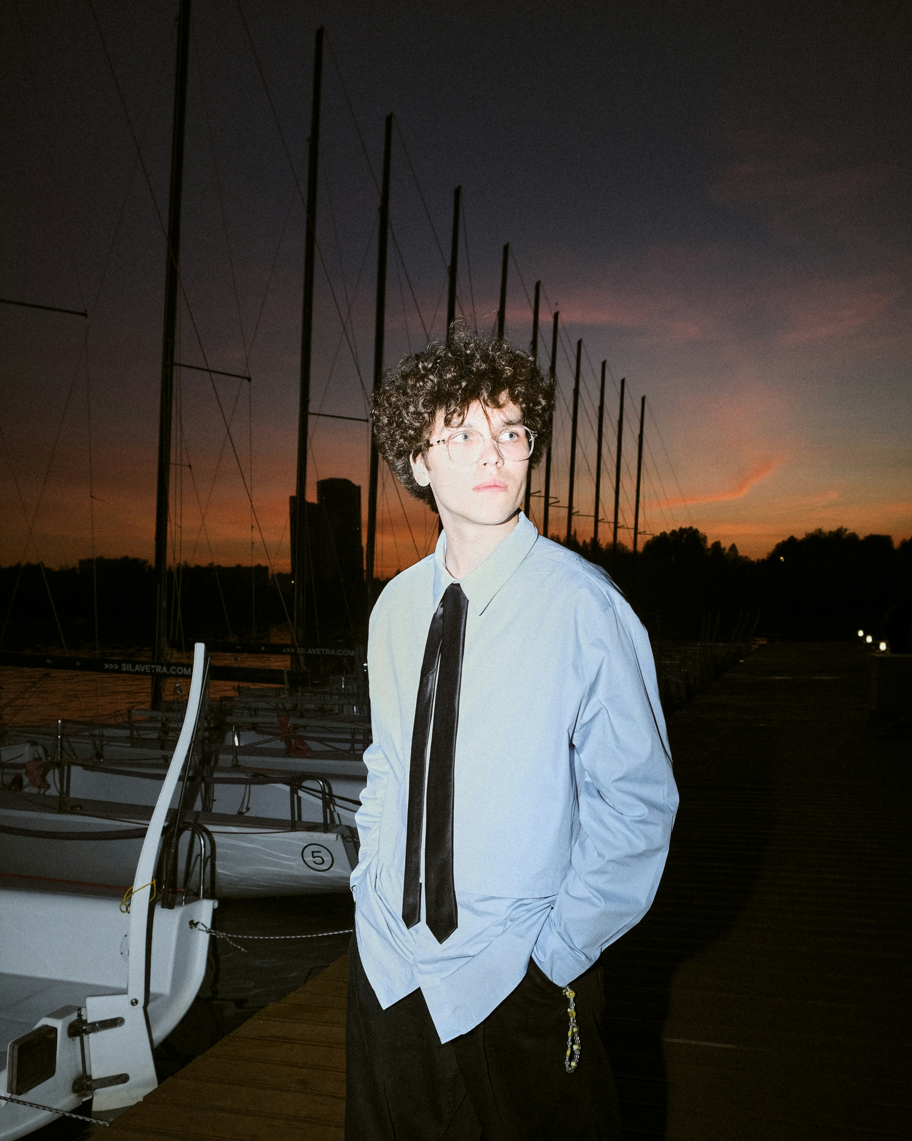 Dusk Portrait by the Marina: Blue Shirt, Black Tie Among Silent Masts