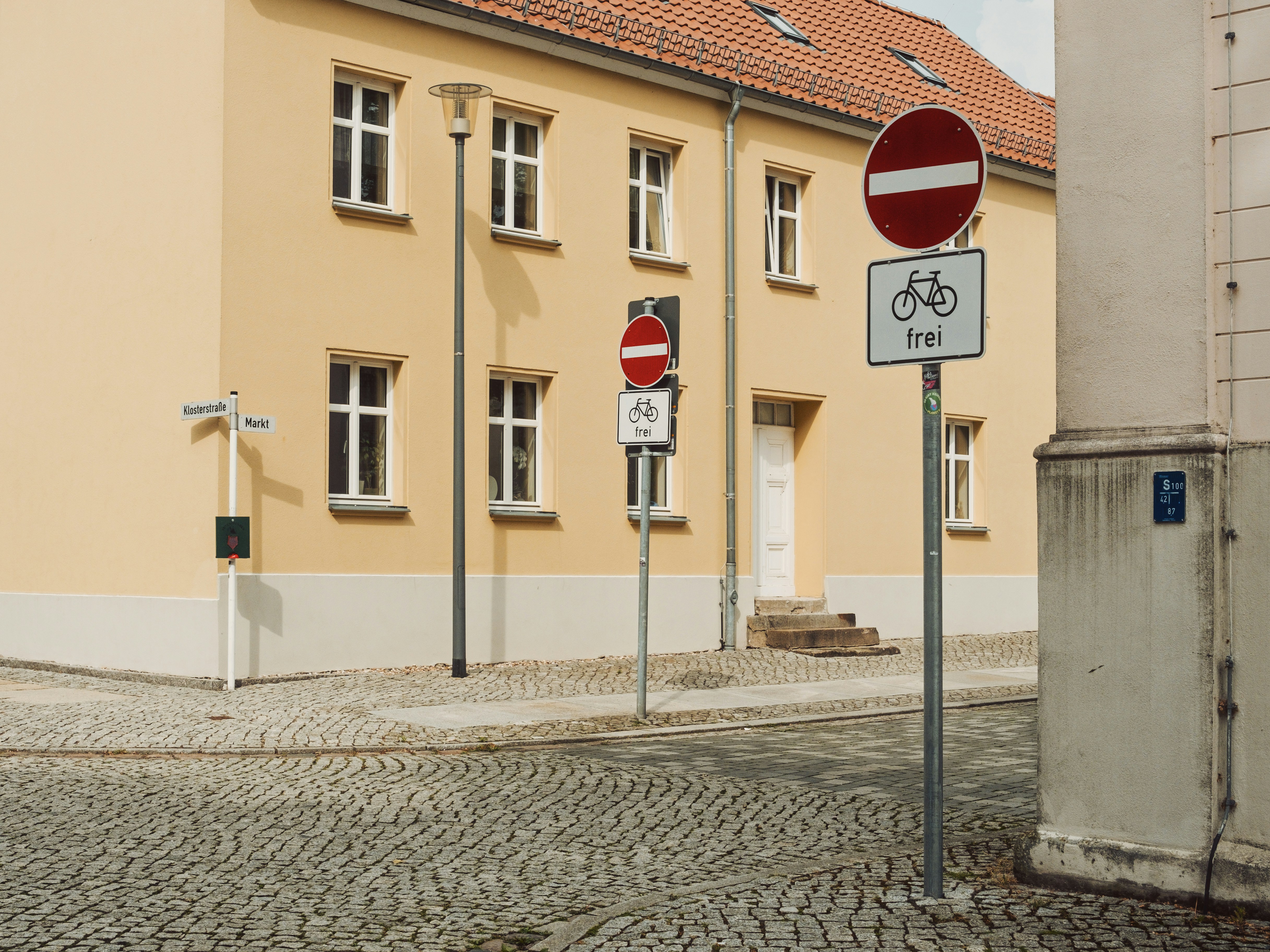 Sunlit Yellow Facade Framed by Signposts on a Cobblestone Corner