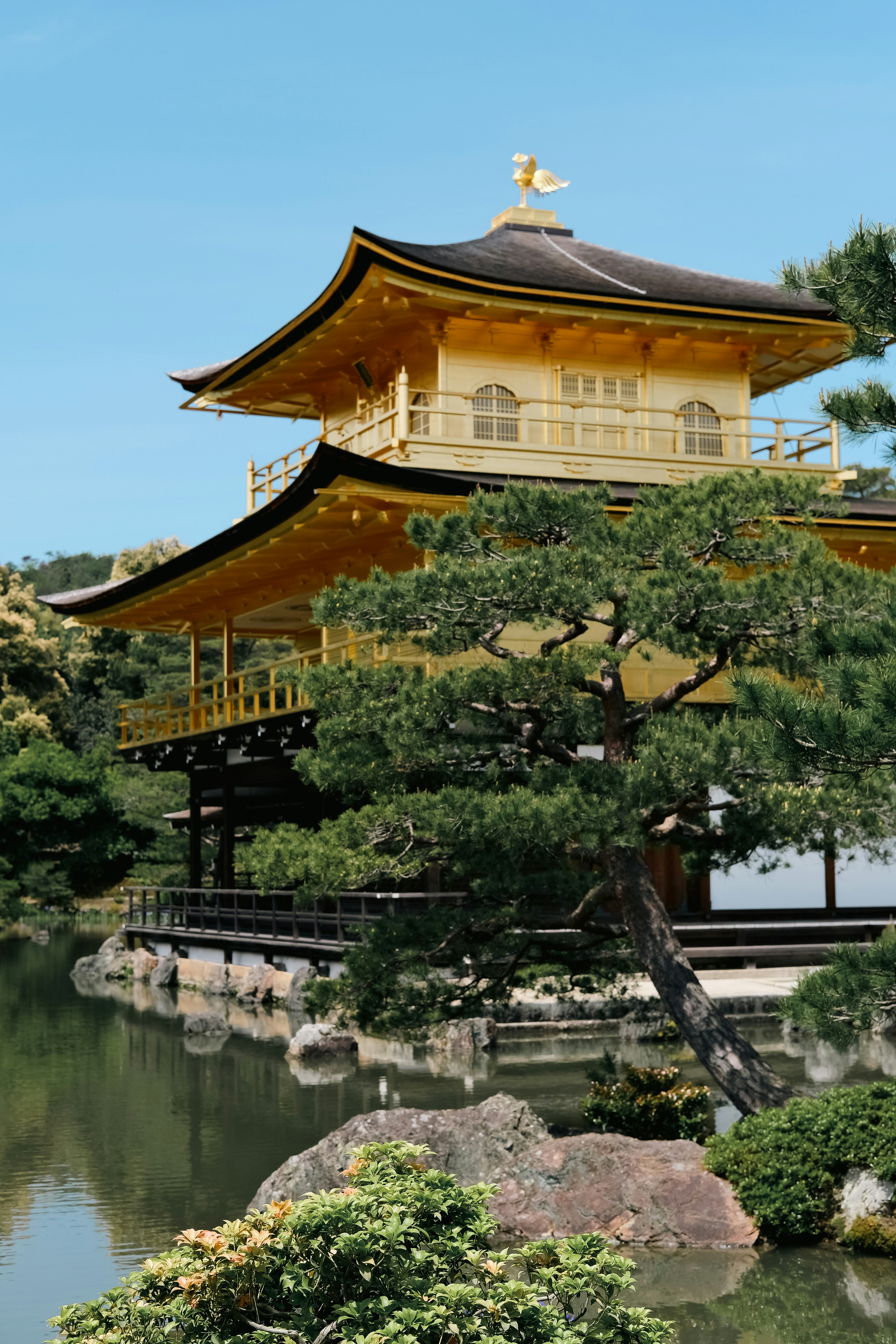 A tall yellow building sitting next to a lake photo – Free Japan Image ...
