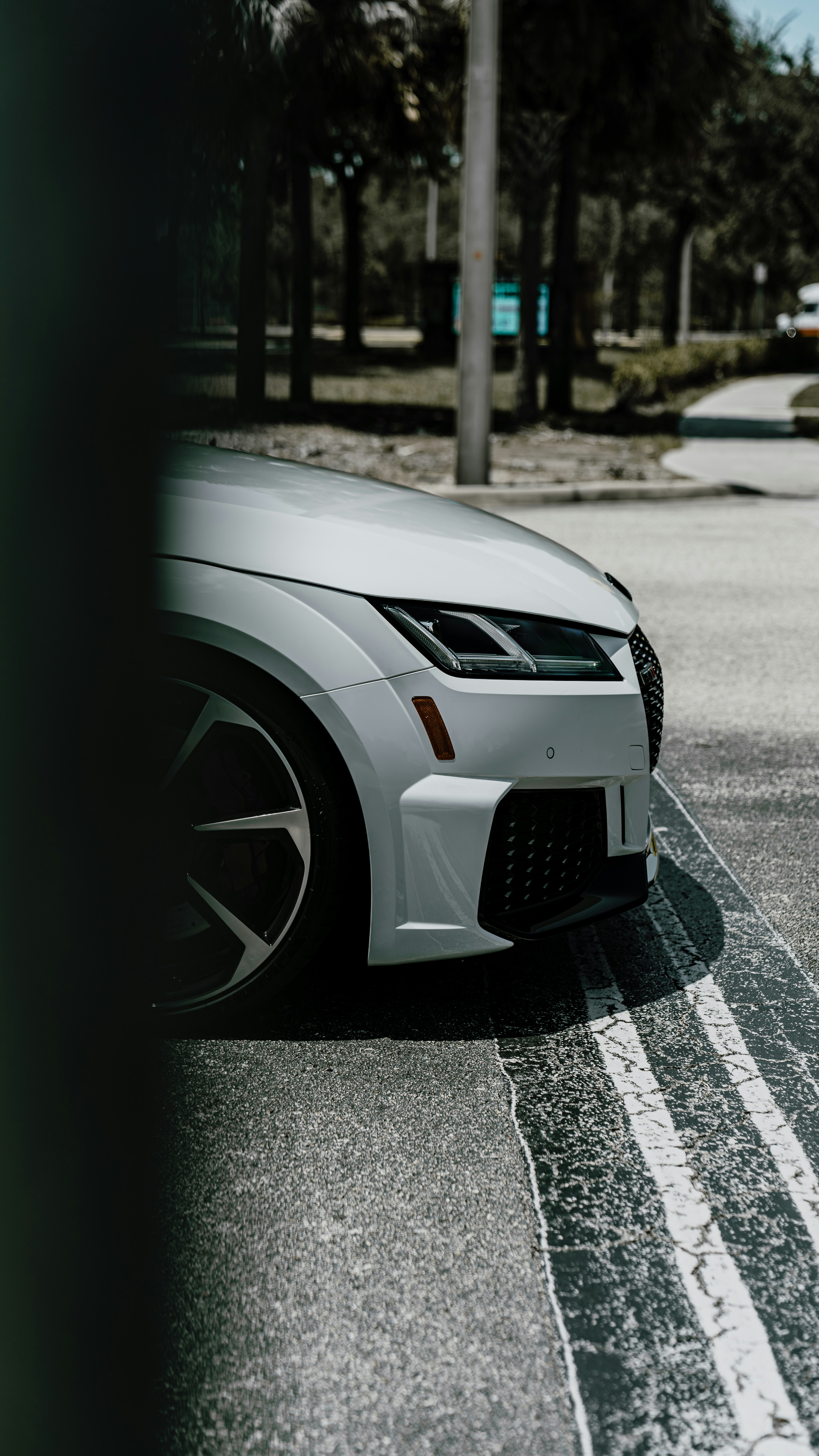 Edge of Velocity: White Performance Sedan Emerging from the Parking Lot Shadow