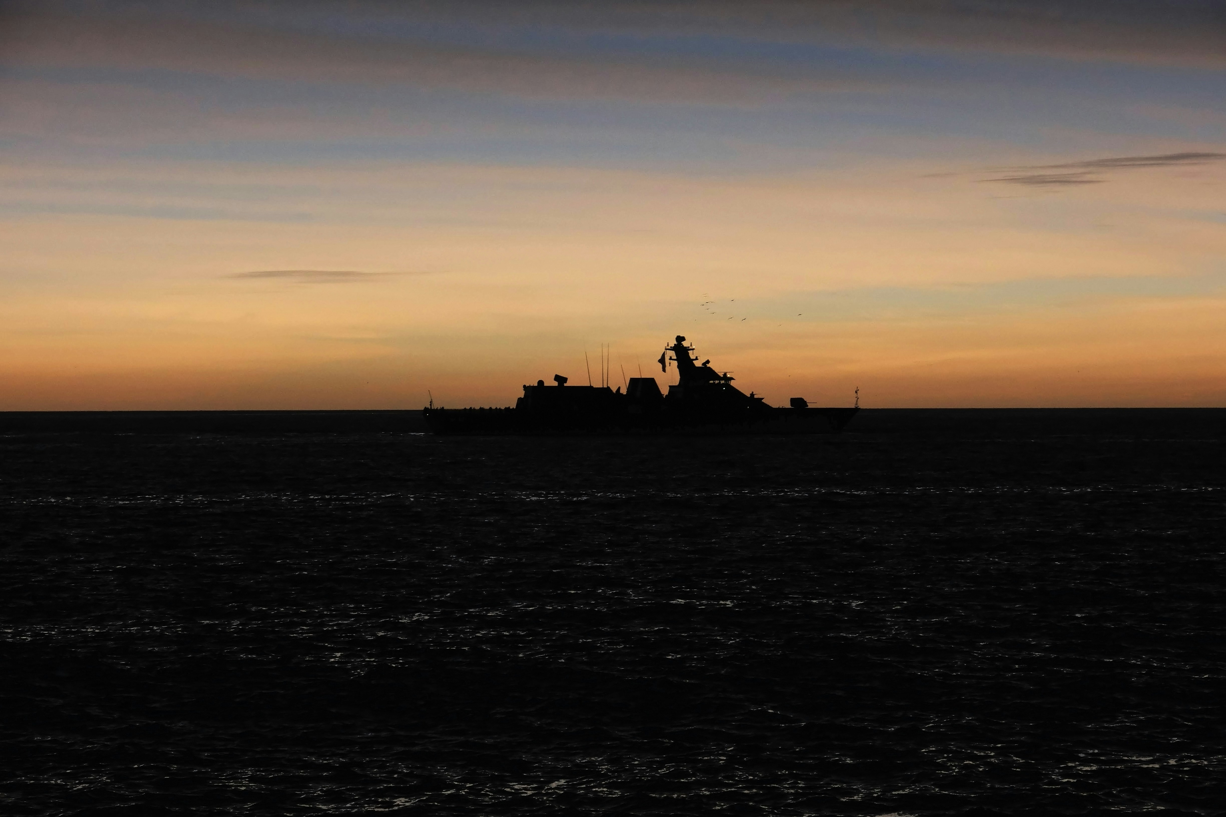 Silhouette of a ship against a dimly lit sea during a solar eclipse in Mazatlan.