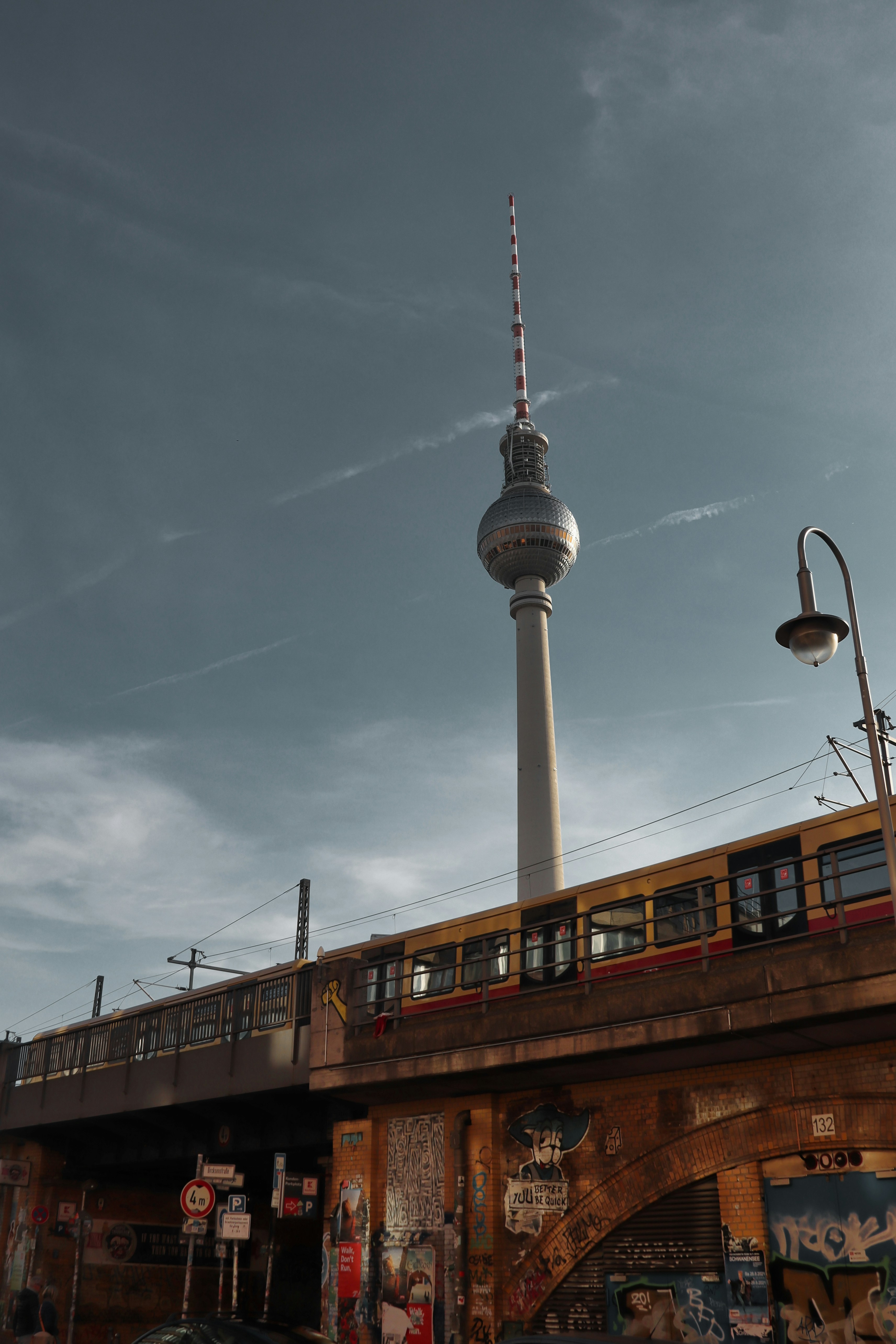 Berlin's Fernsehturm Soars Above Graffiti-Arched Transit Corridor