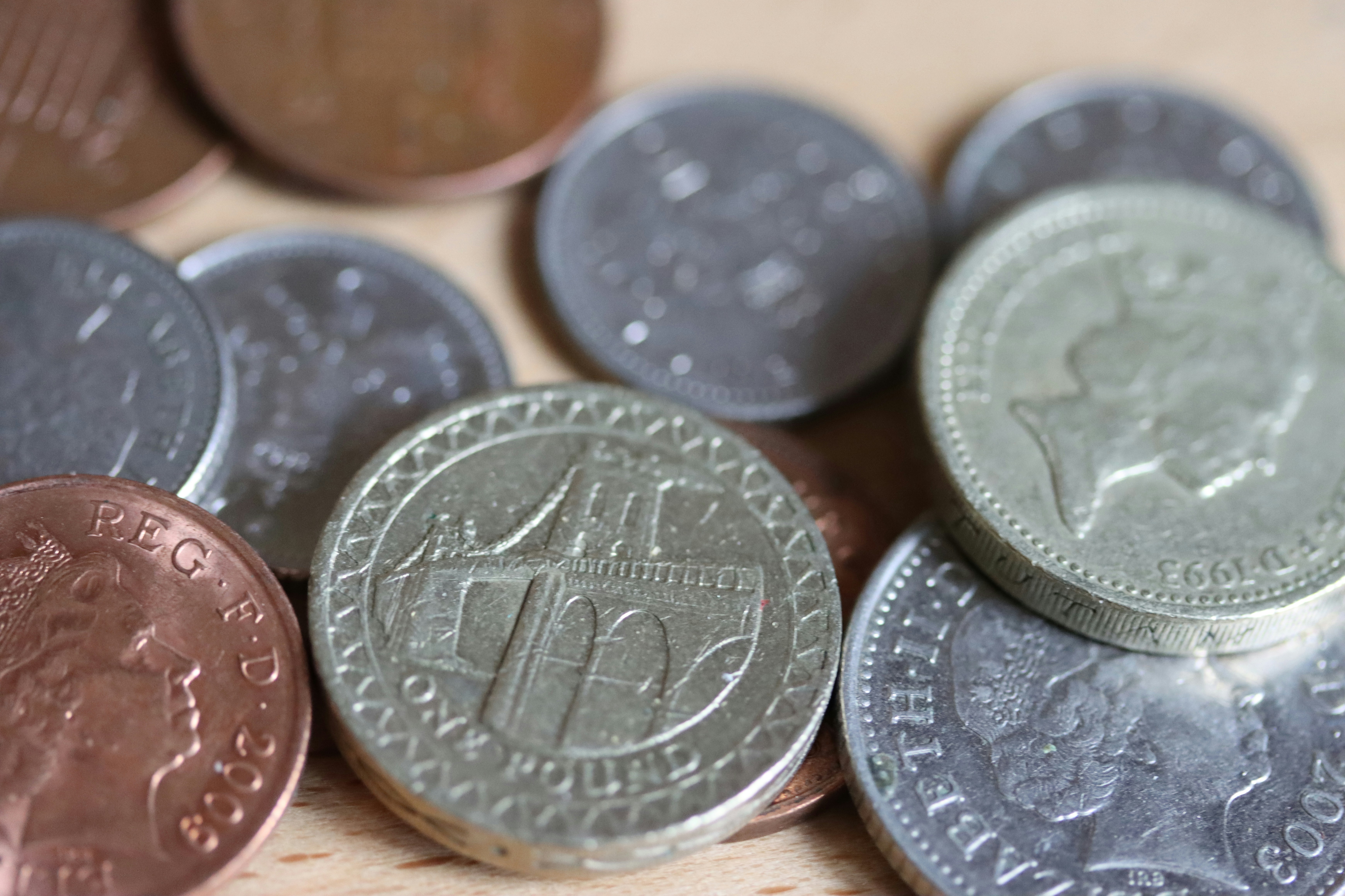 Assorted British coins scattered on a wooden surface.