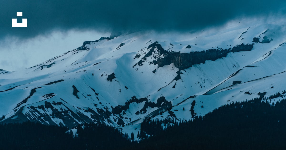 Une Montagne Couverte De Neige Sous Un Ciel Nuageux Photo Image