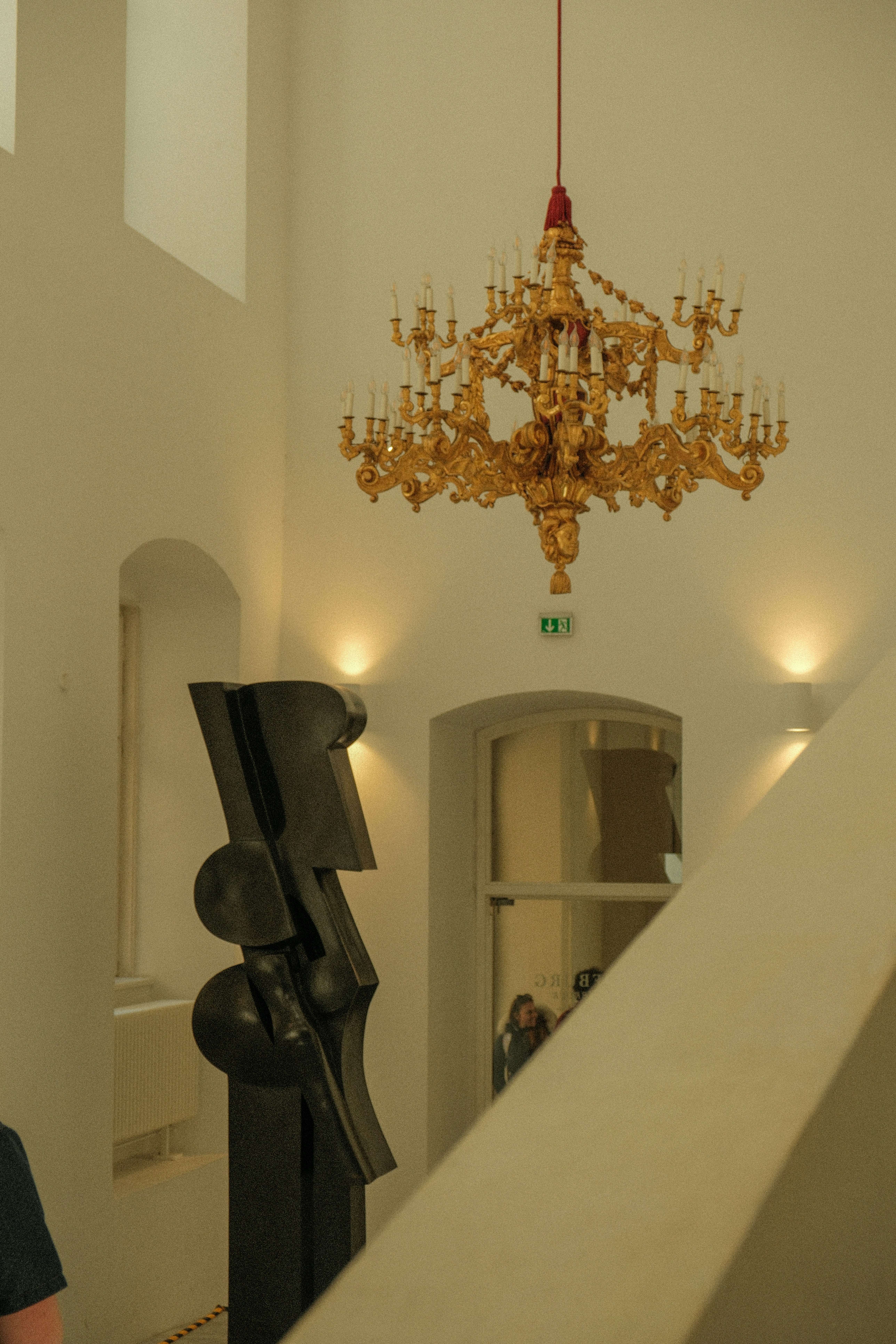 Gilded Chandelier Over a Quiet Gallery Staircase
