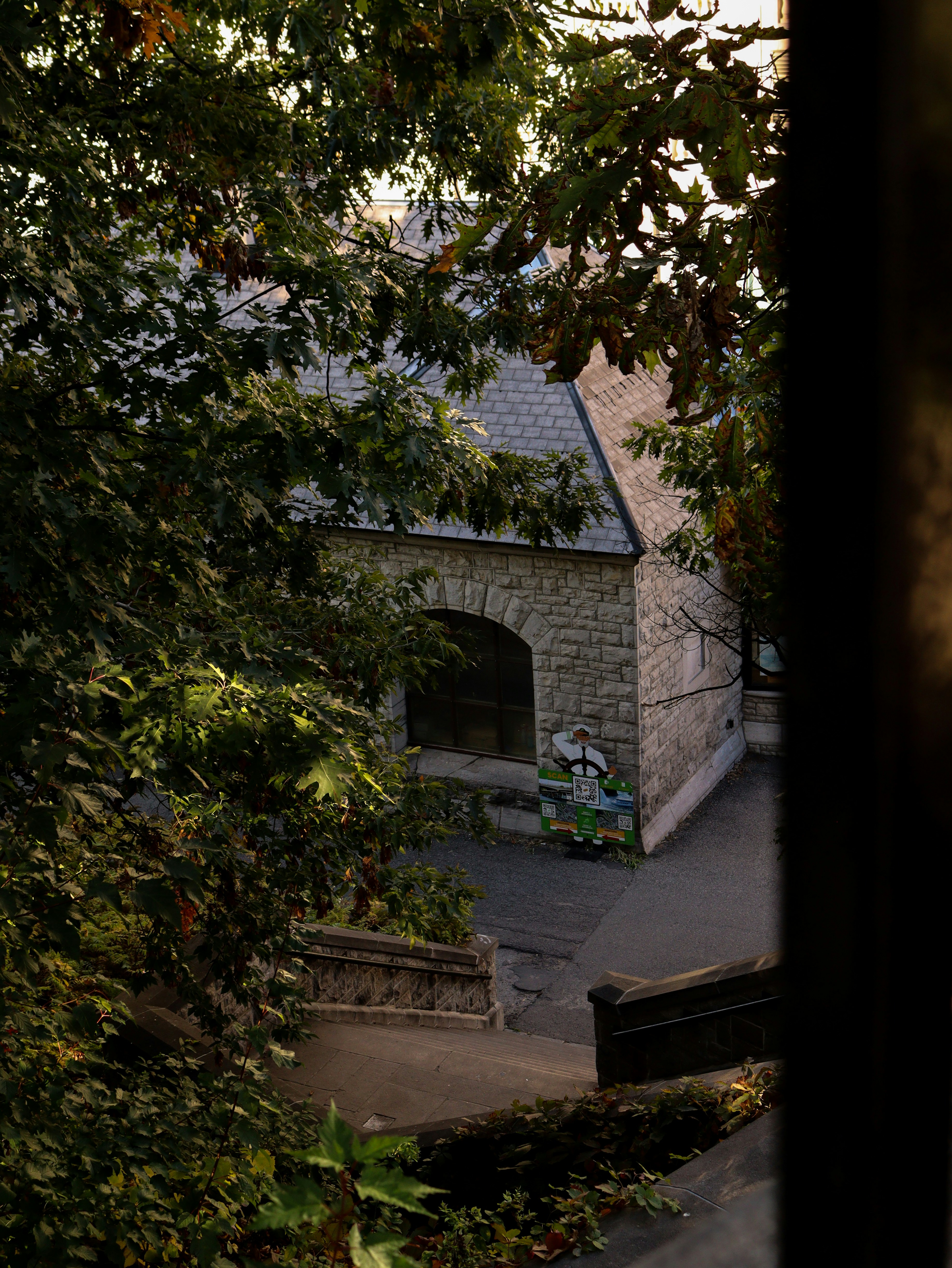 Stone Archway Framed by Tree Canopy on a Quiet Street