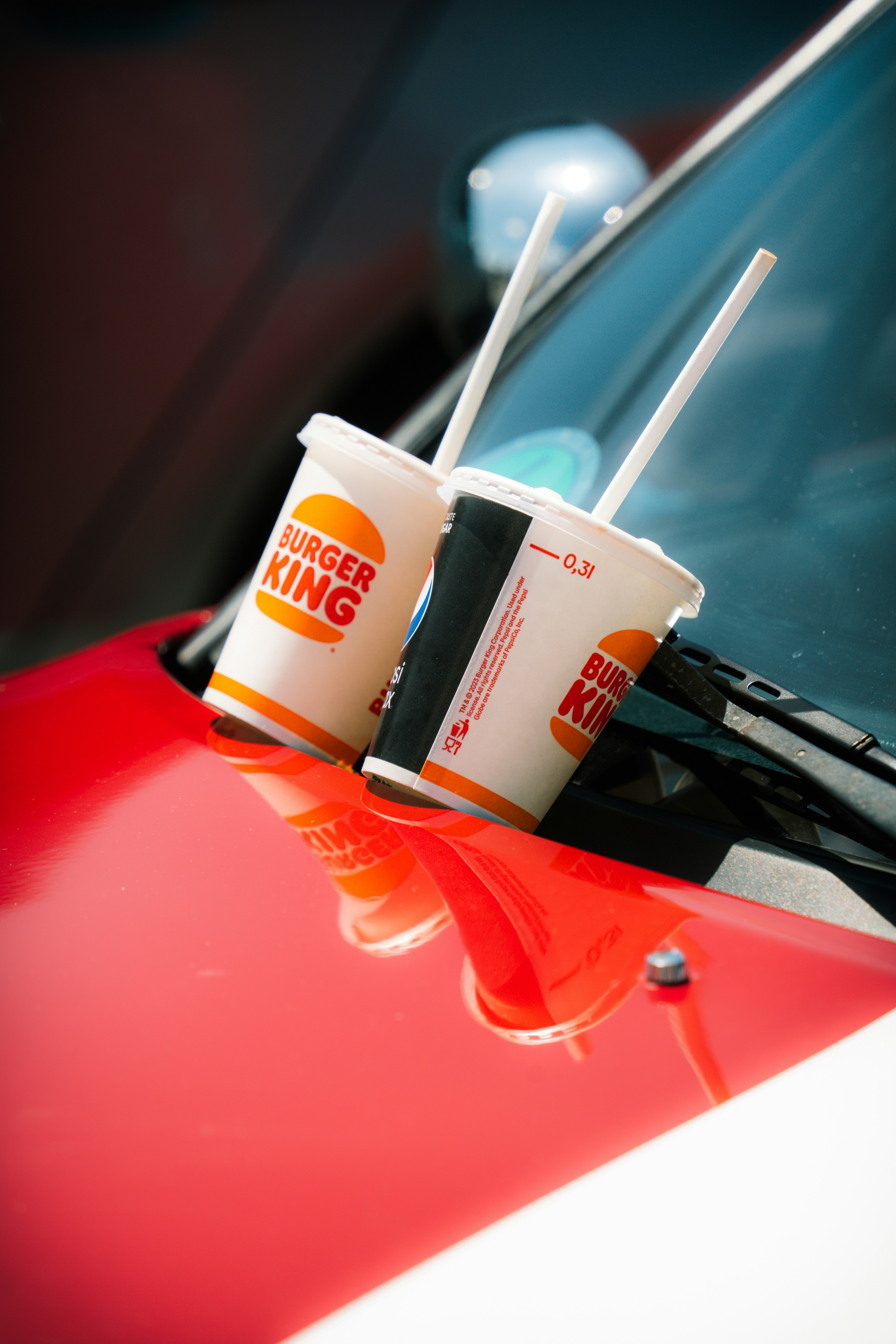 Crimson Hood Duo: Burger King Cups Perched on a Glossy Car Surface