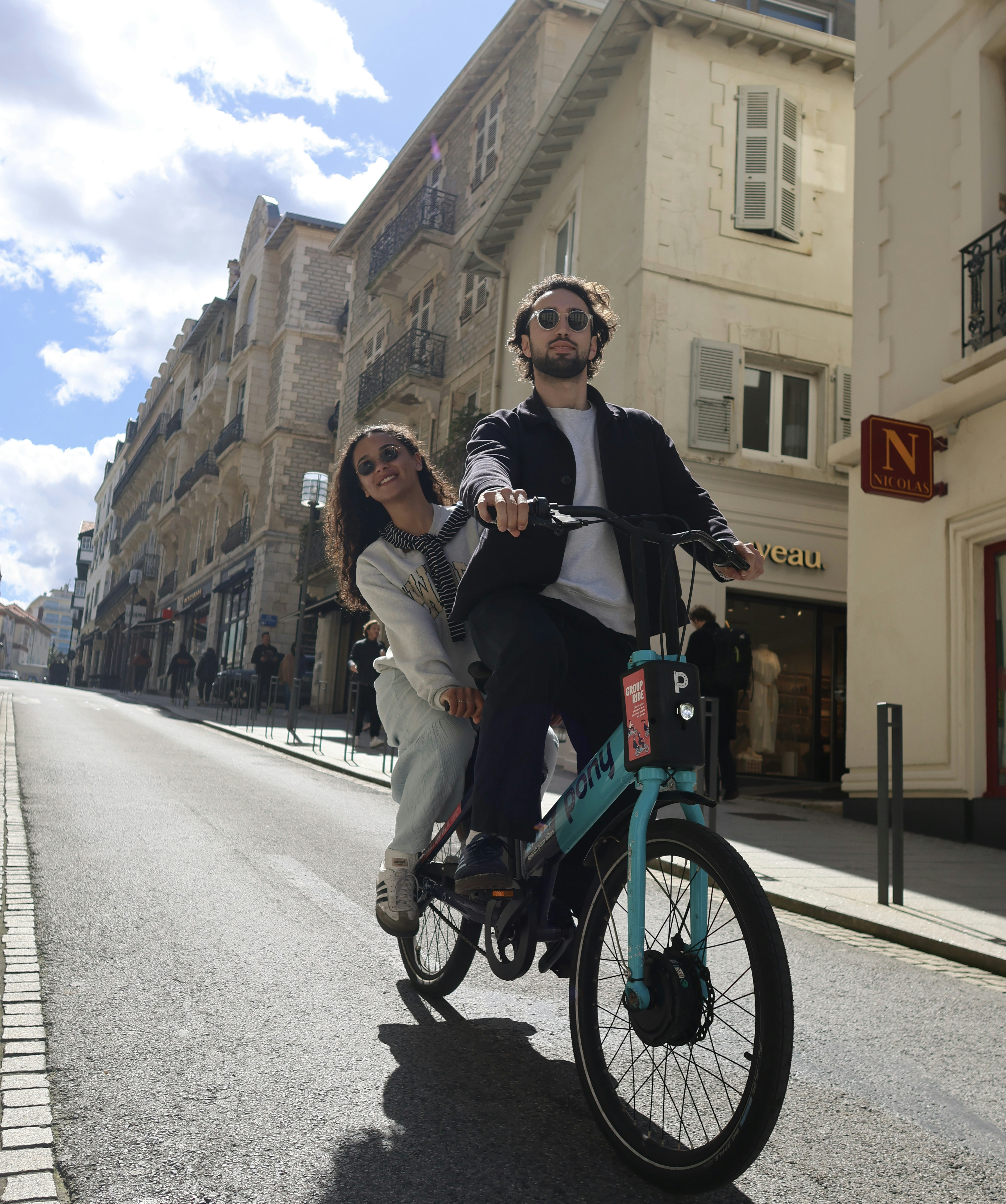 Turquoise E-Bike Duo Navigates a Sunlit European Street
