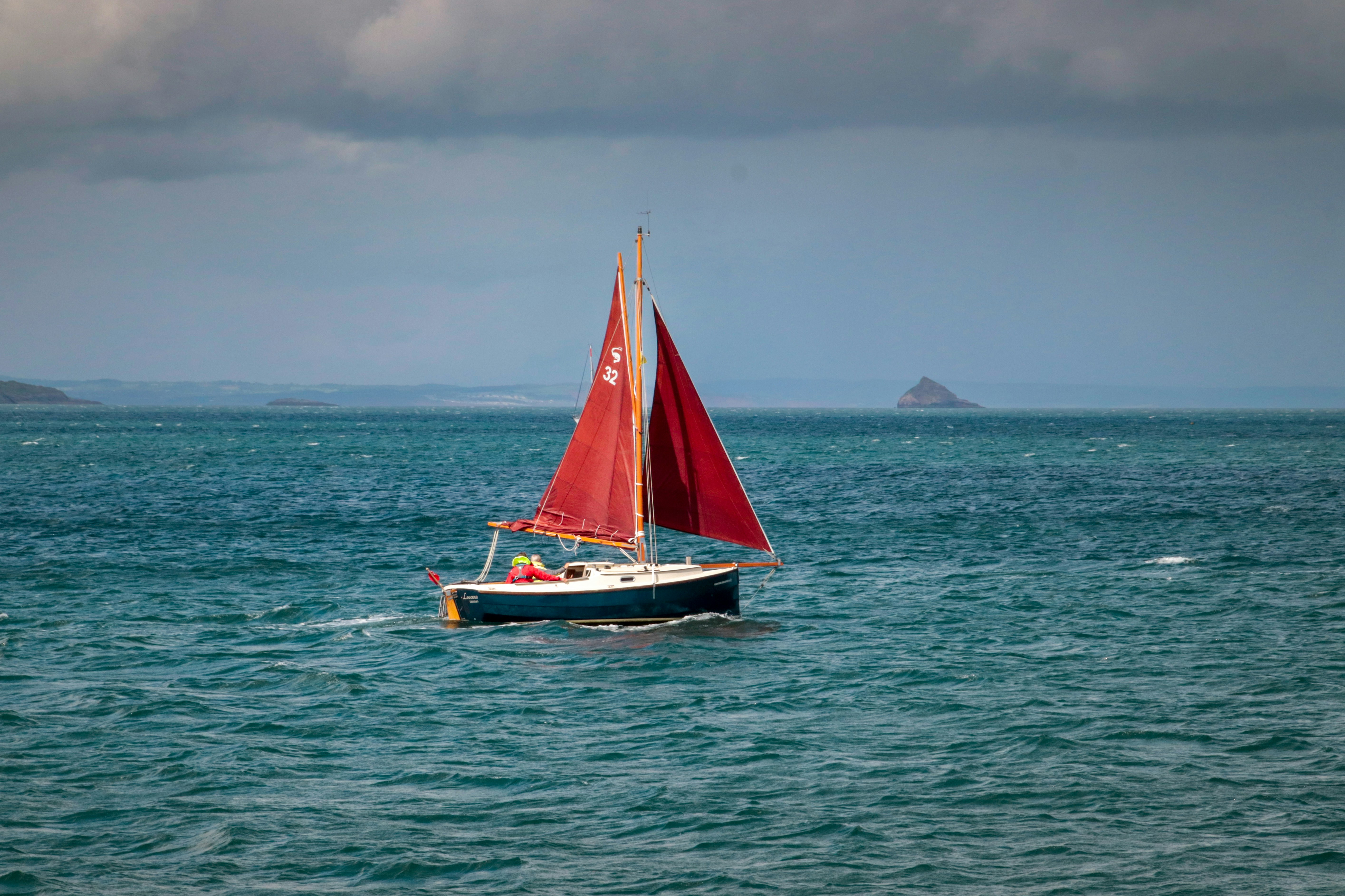 A sailboat with red sails in the ocean photo – Free Sailboat Image on ...