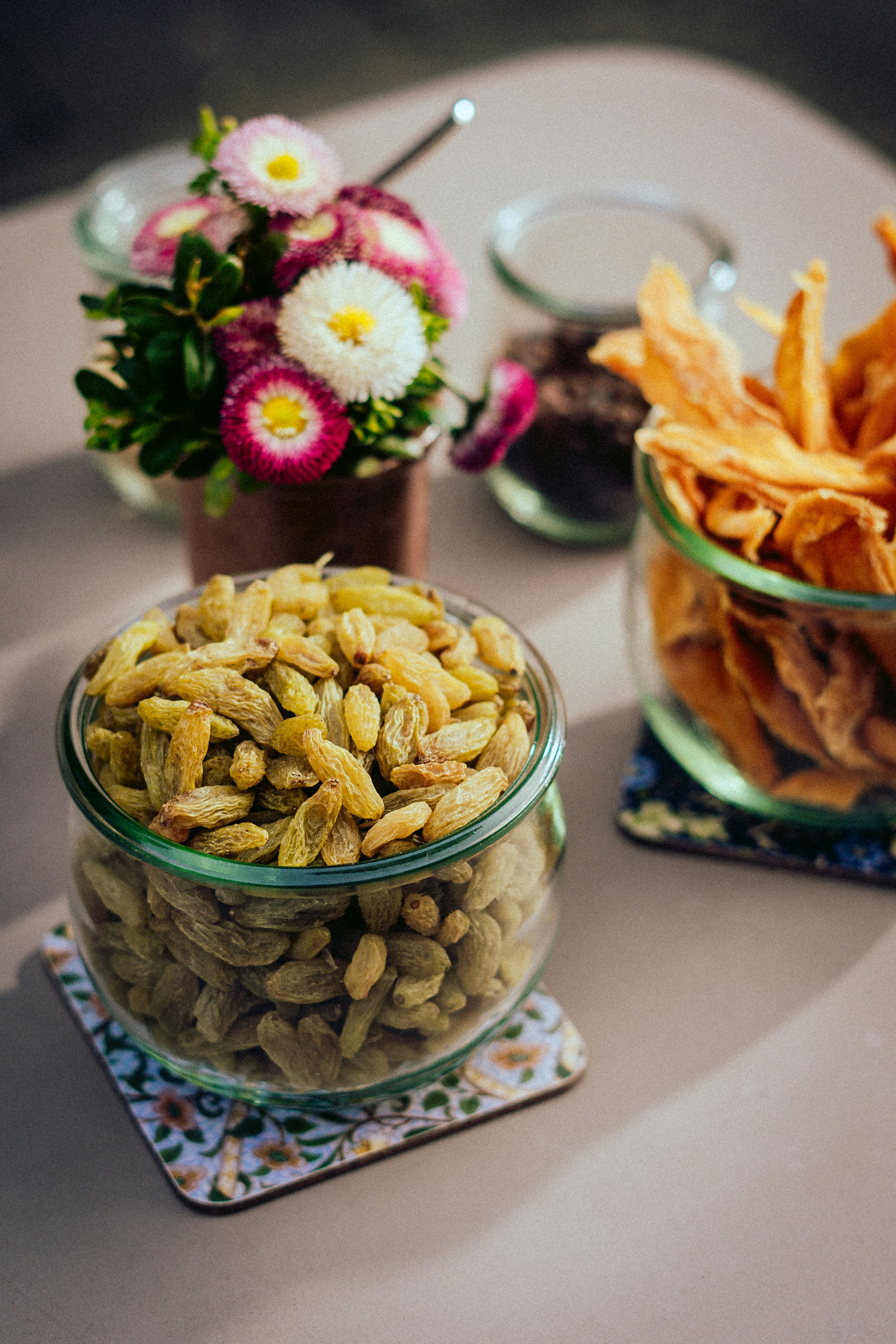 Golden Raisins in a Glass Jar: A Quiet Tabletop Still Life with Floral Accent