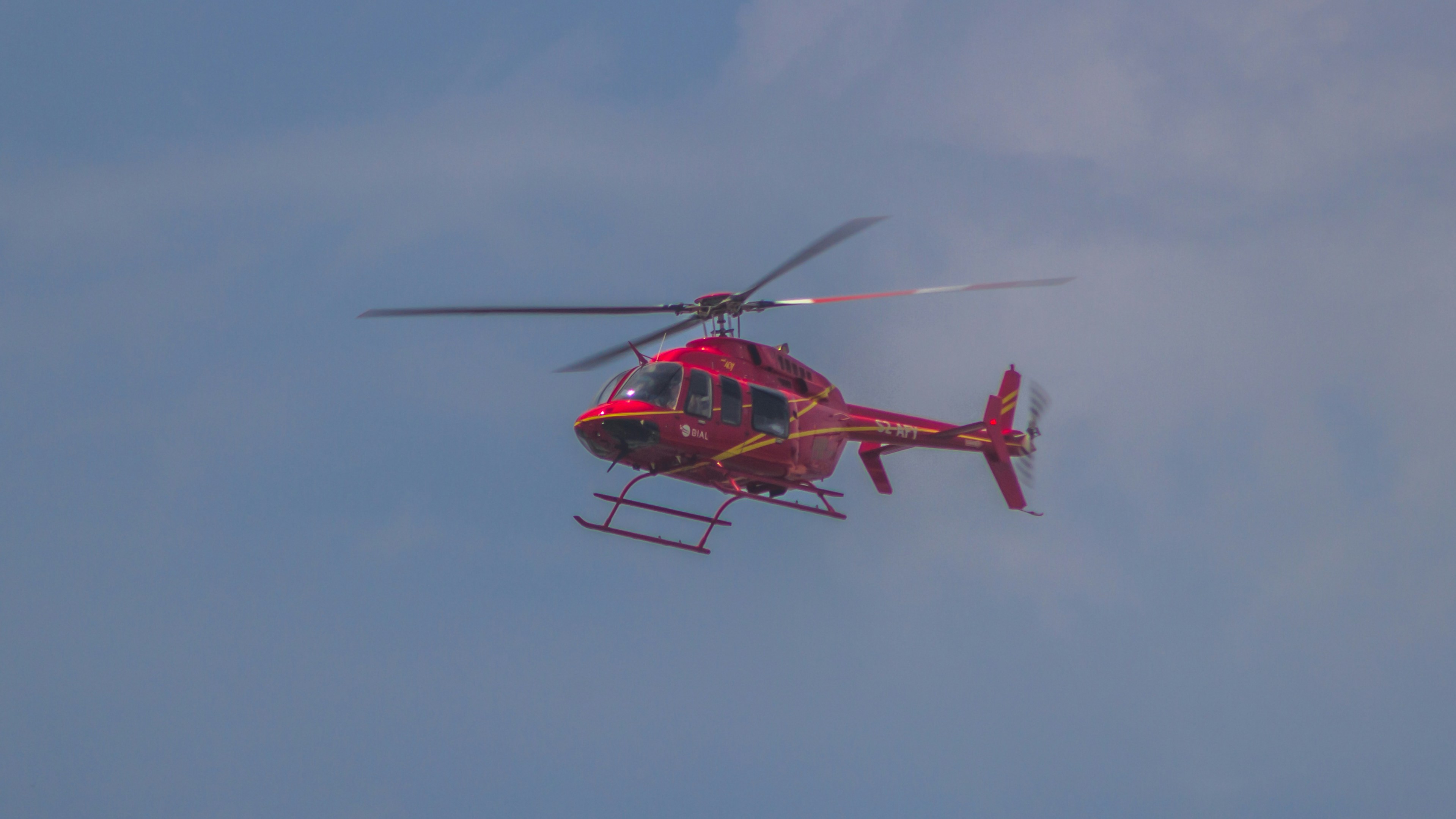 A red helicopter flying through a blue sky photo – Free Flying Image on ...