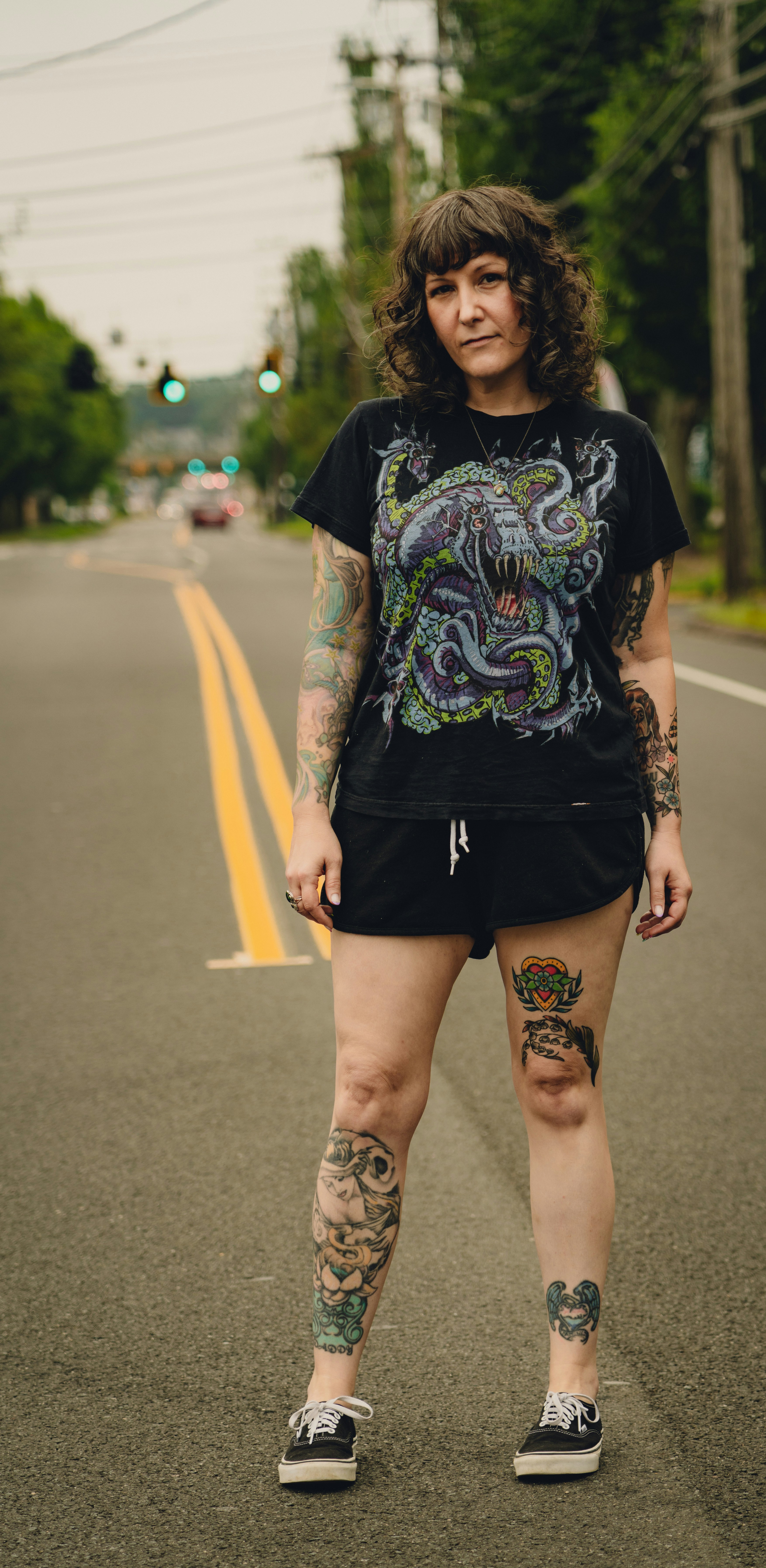 Ink and Asphalt: A Tattooed Wanderer Stands Under Green Lights