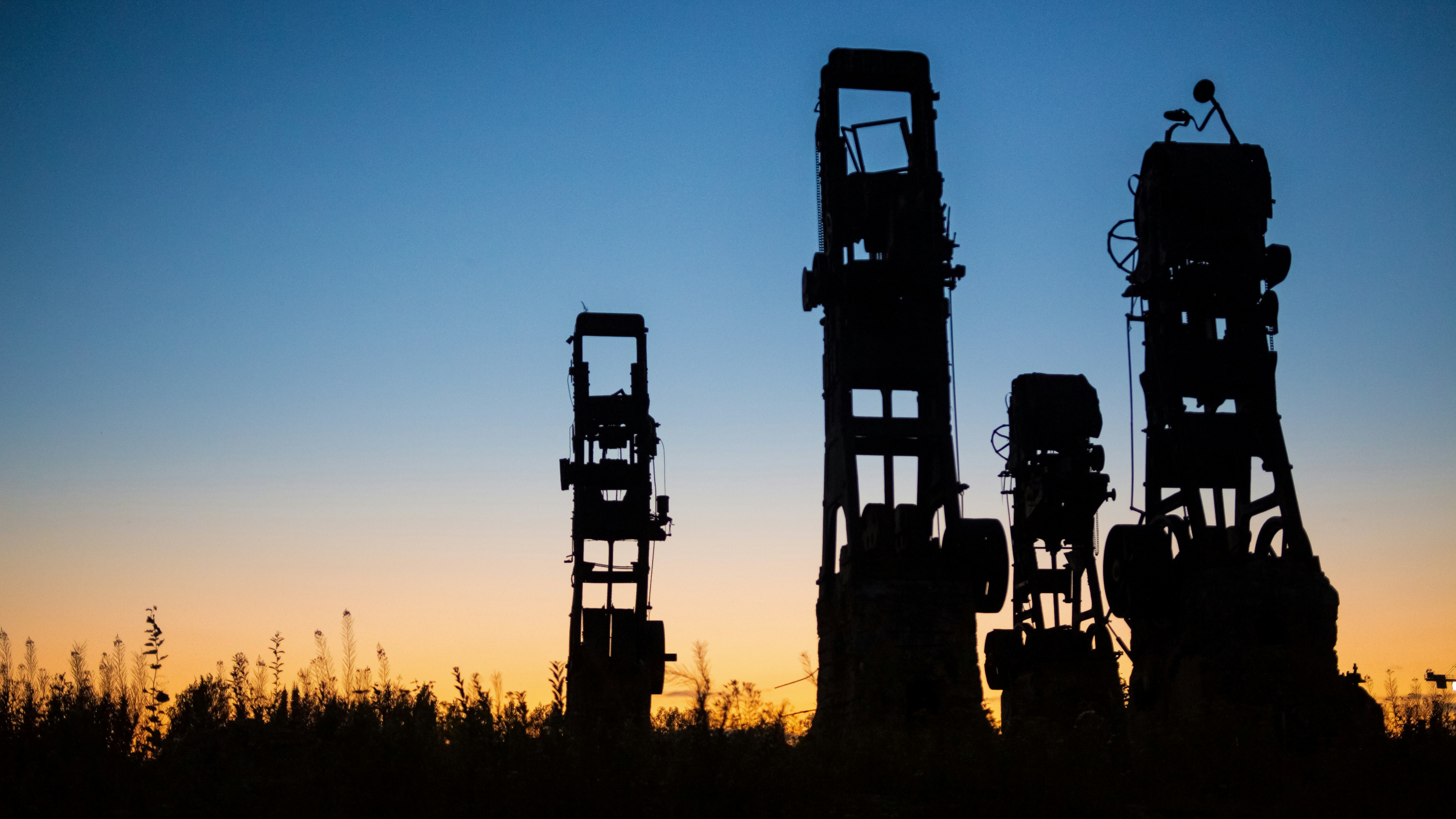Silhouetted industrial structures stand against a twilight sky, marking the remnants of a bygone era.