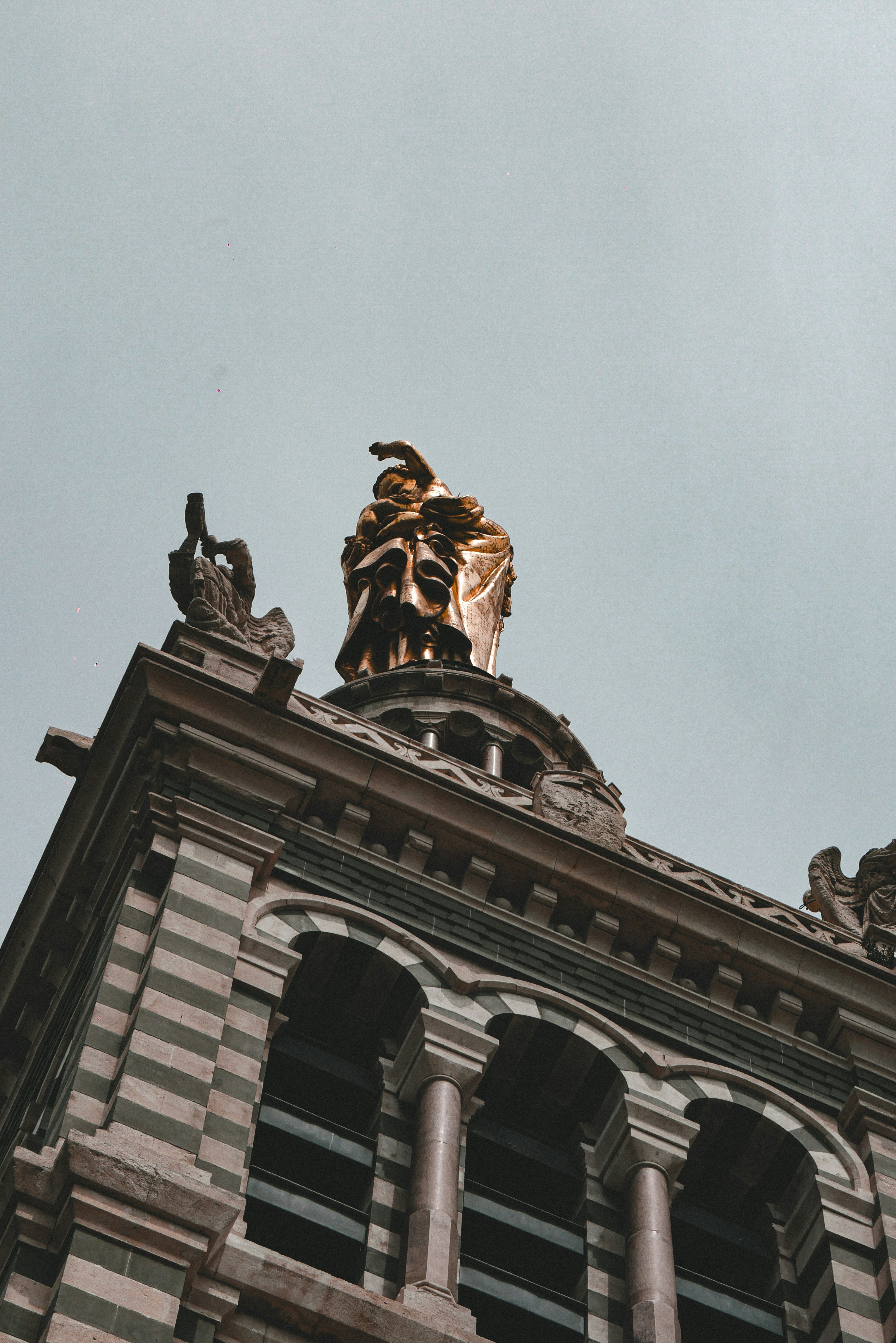 Bronze Guardian Over a Striped Facade: A Low-Angle Monument Portrait