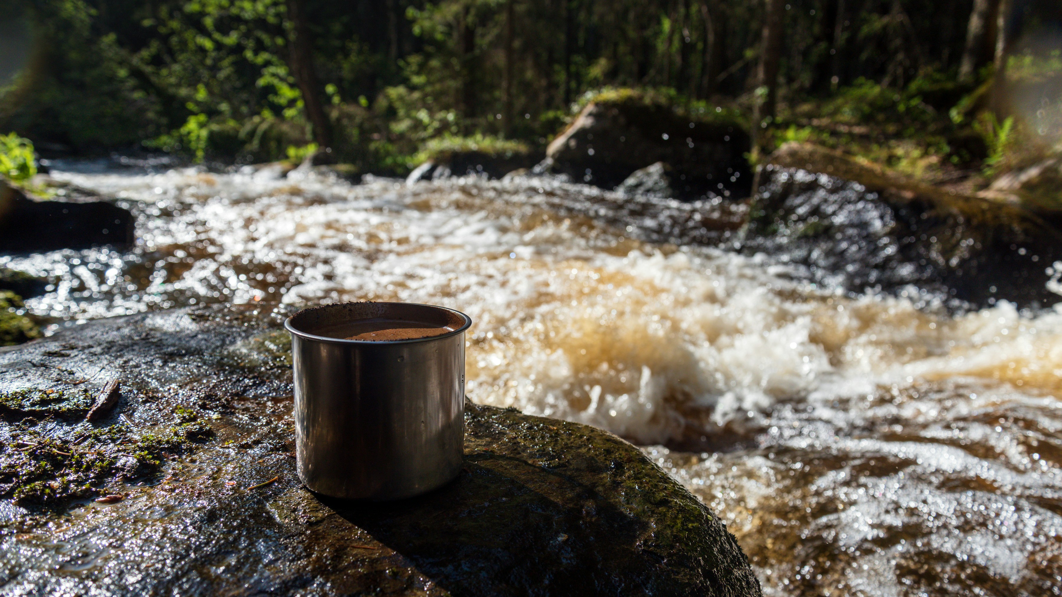 Rusty Cup on a Wet Rock Overlooking a Cascading Stream