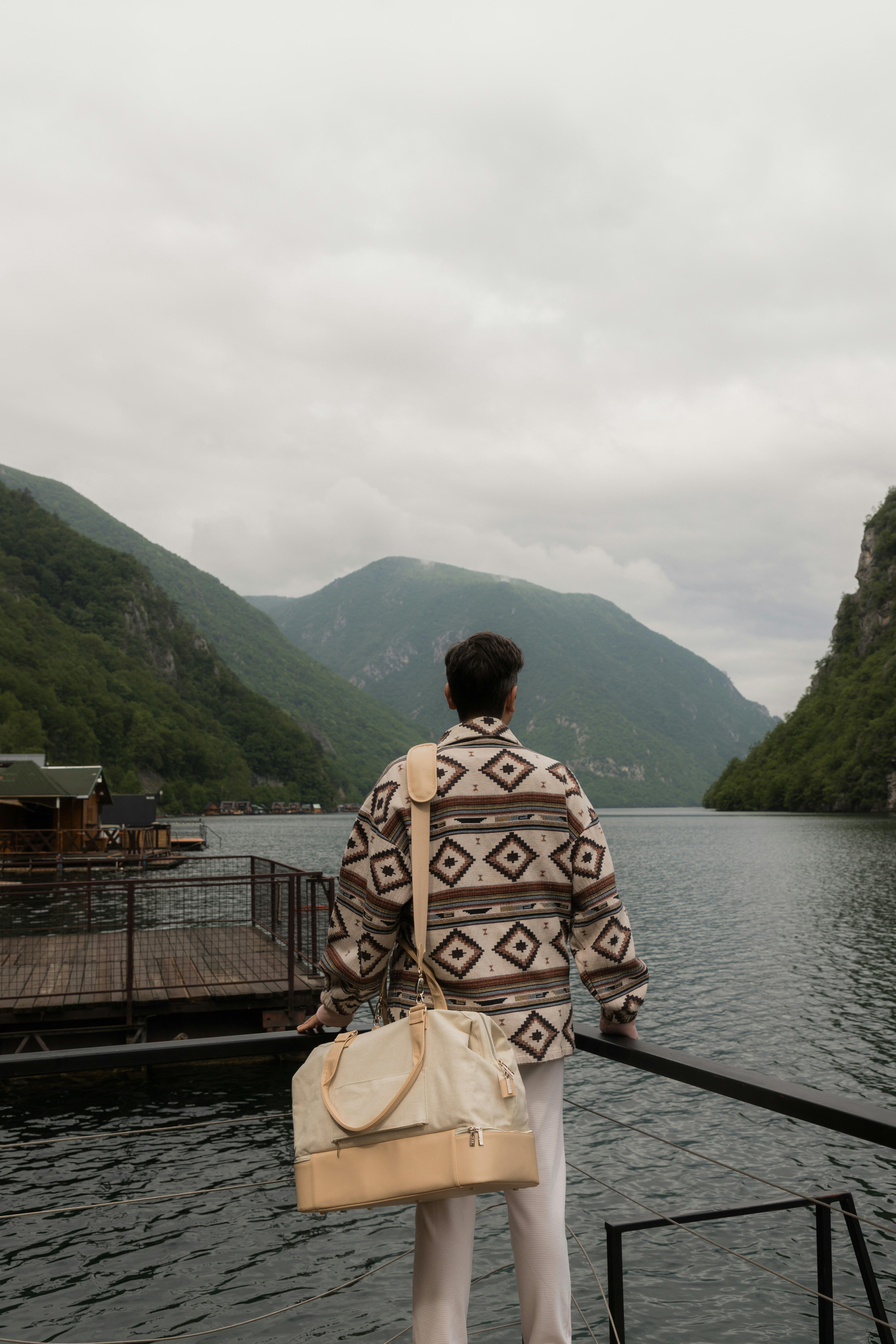 Traveler in a patterned sweater gazes over a tranquil fjord