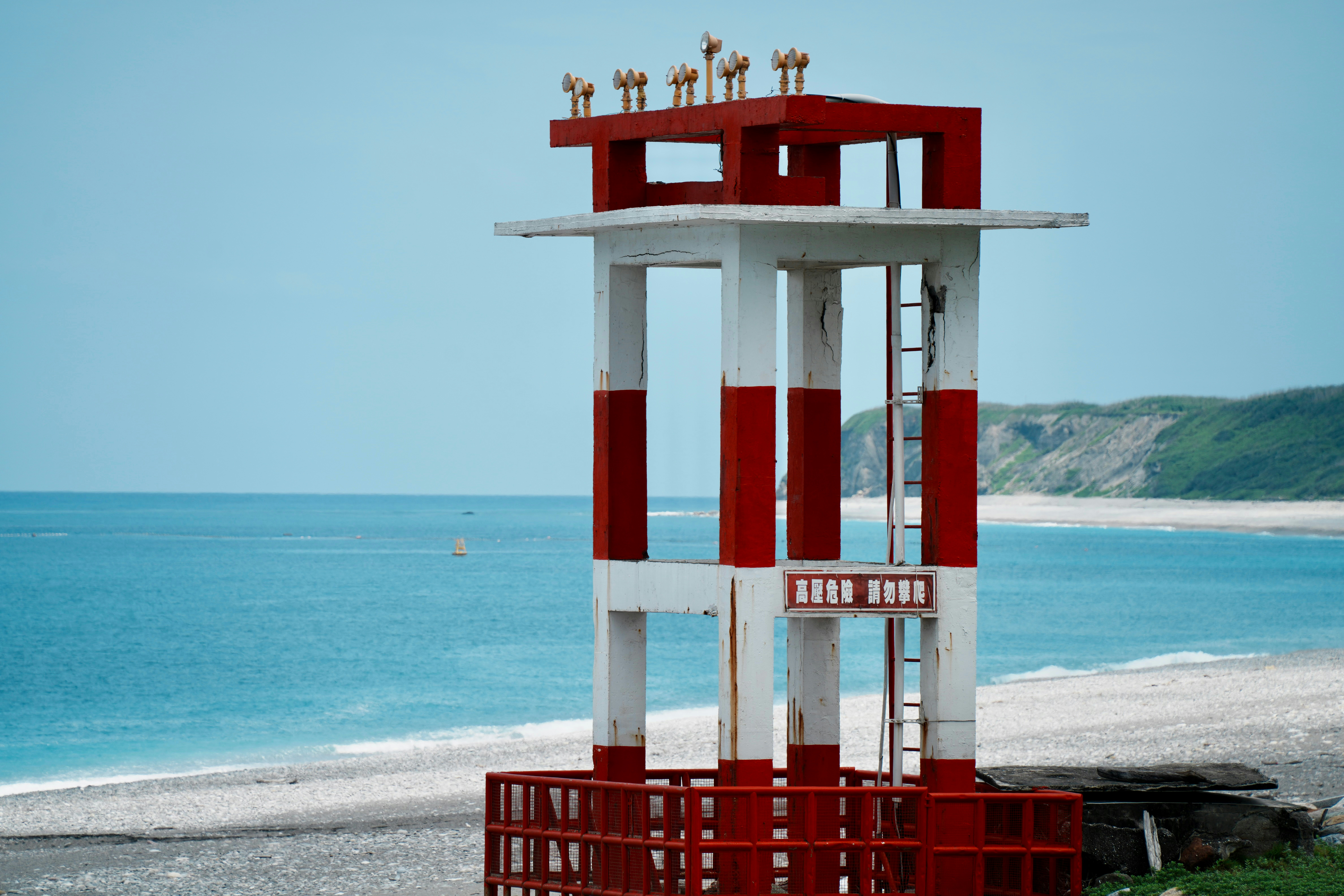 Sentinel of the Shore: A Red-and-White Lifeguard Tower Beside Turquoise Seas