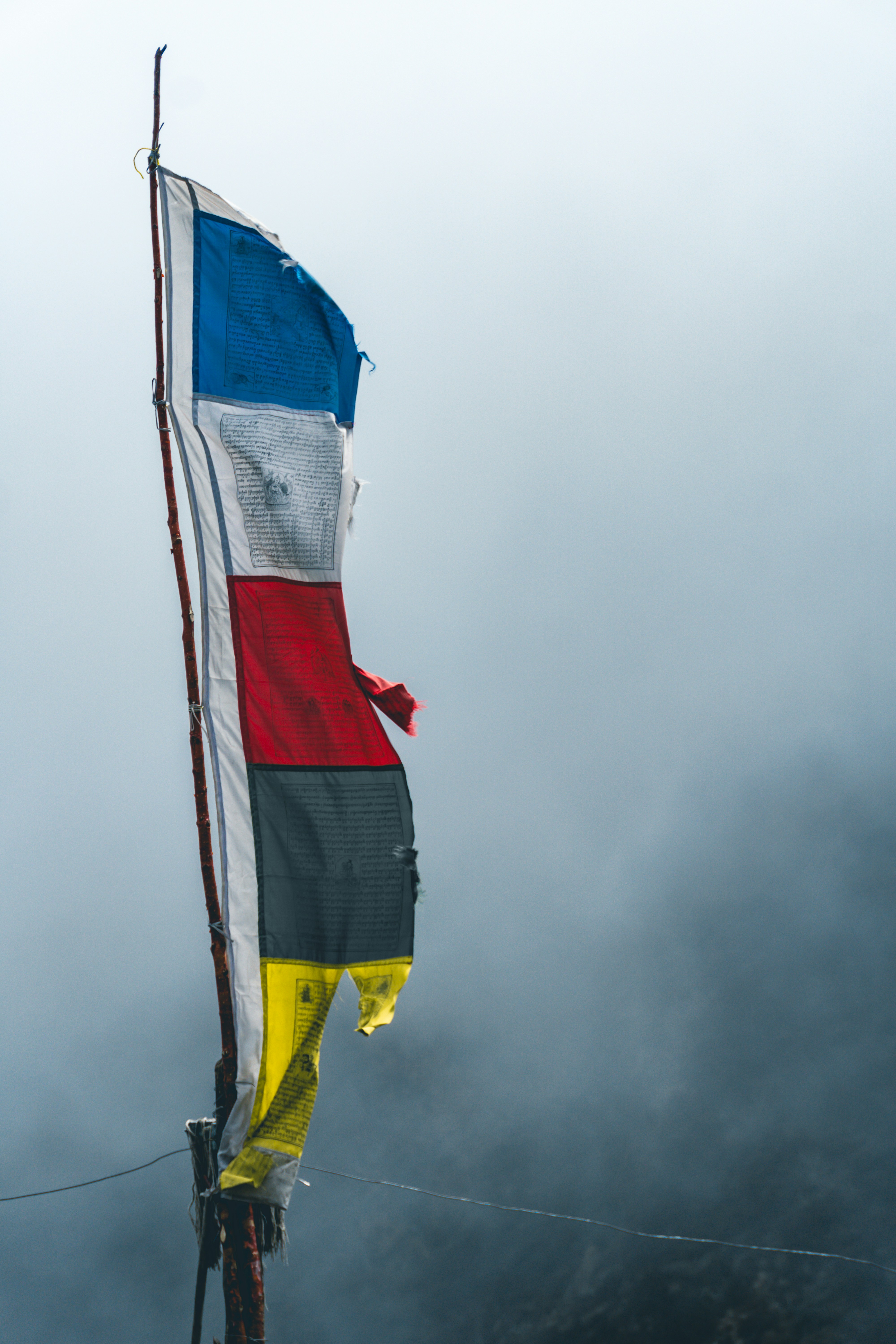 Tattered Prism on a Lone Flagpole Against Misty Mountains