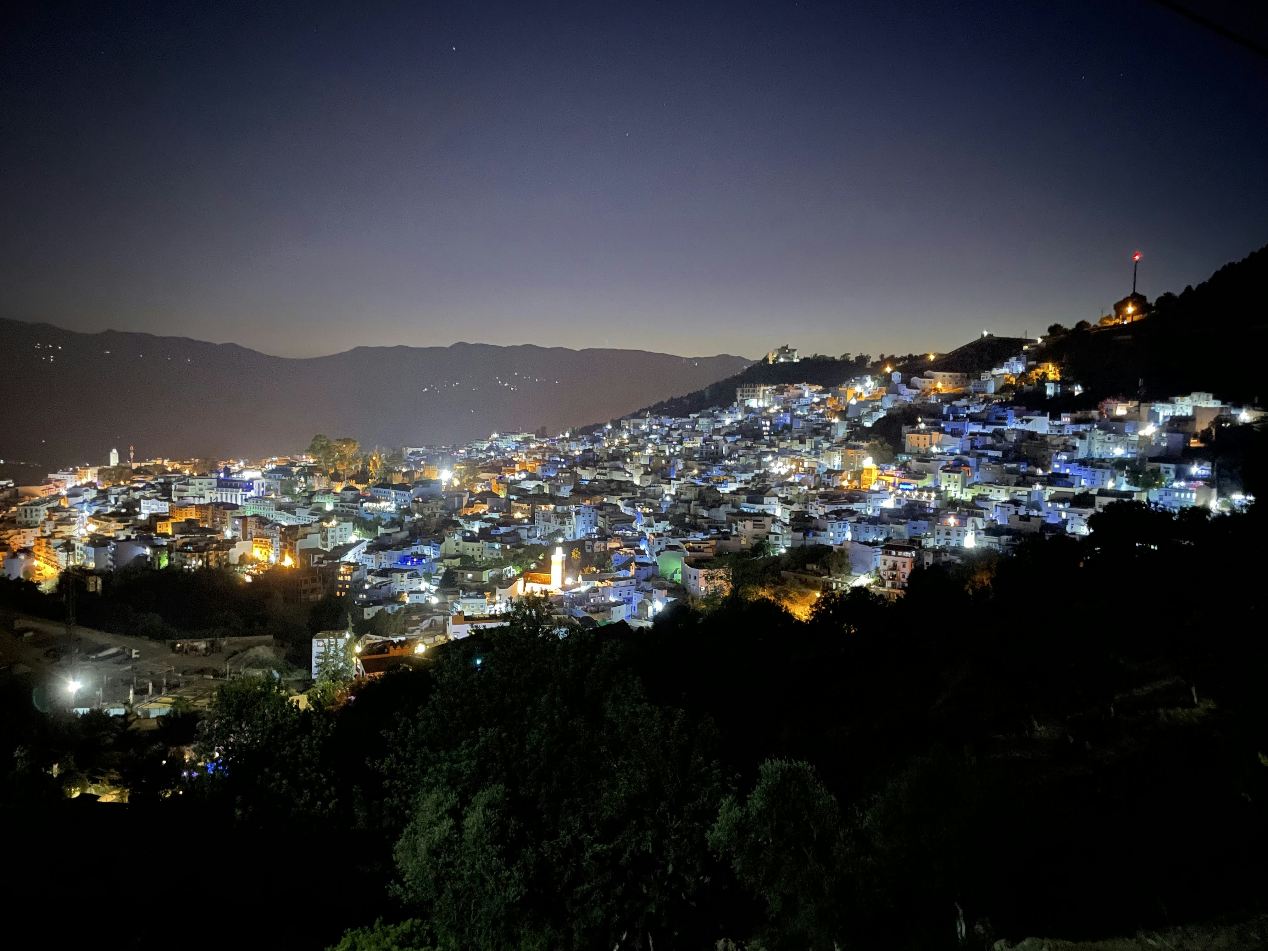 Nightfall in a hillside city: glowing terraces cascade across the valley