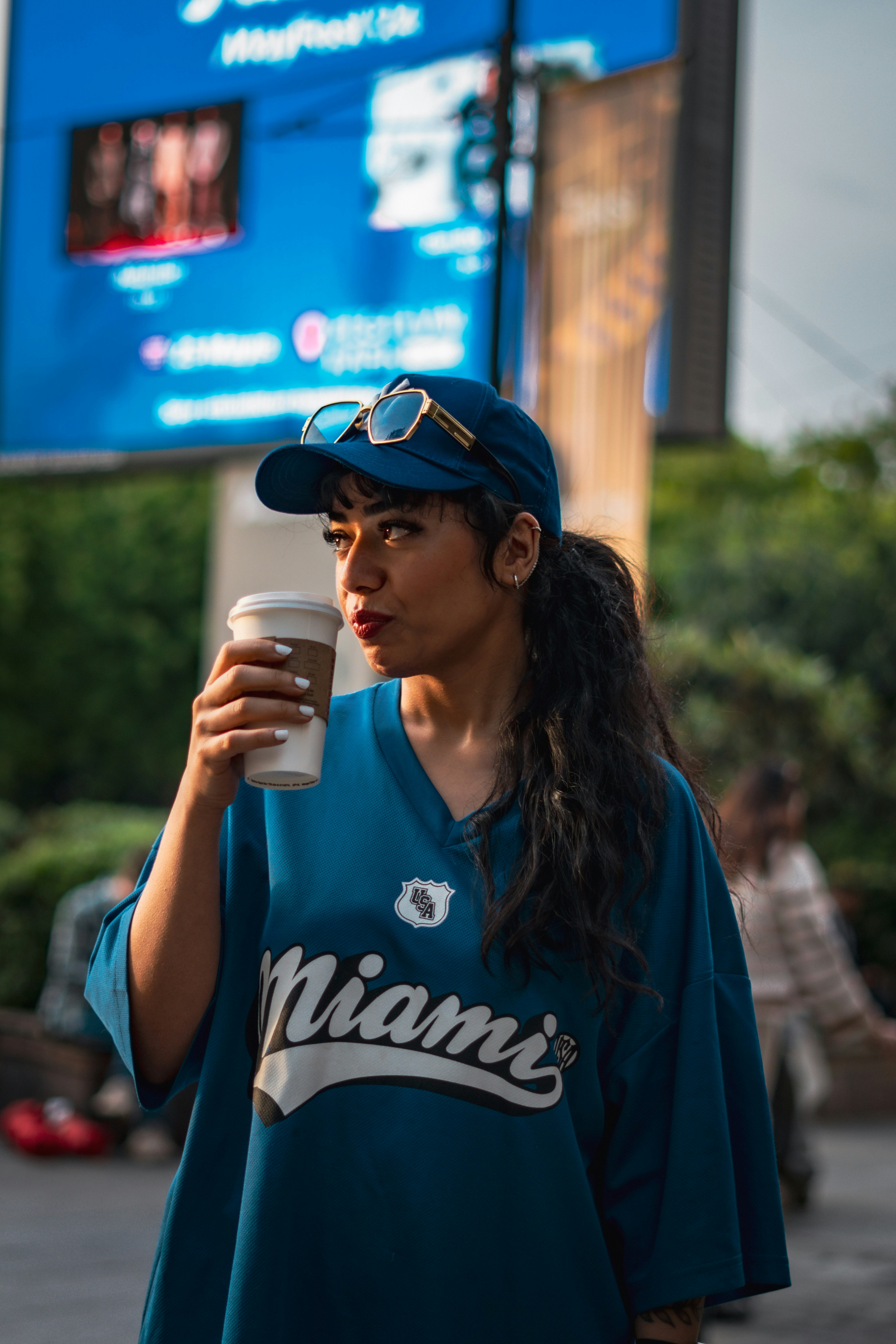 A woman in a baseball uniform holding a cup of coffee photo – Free ...