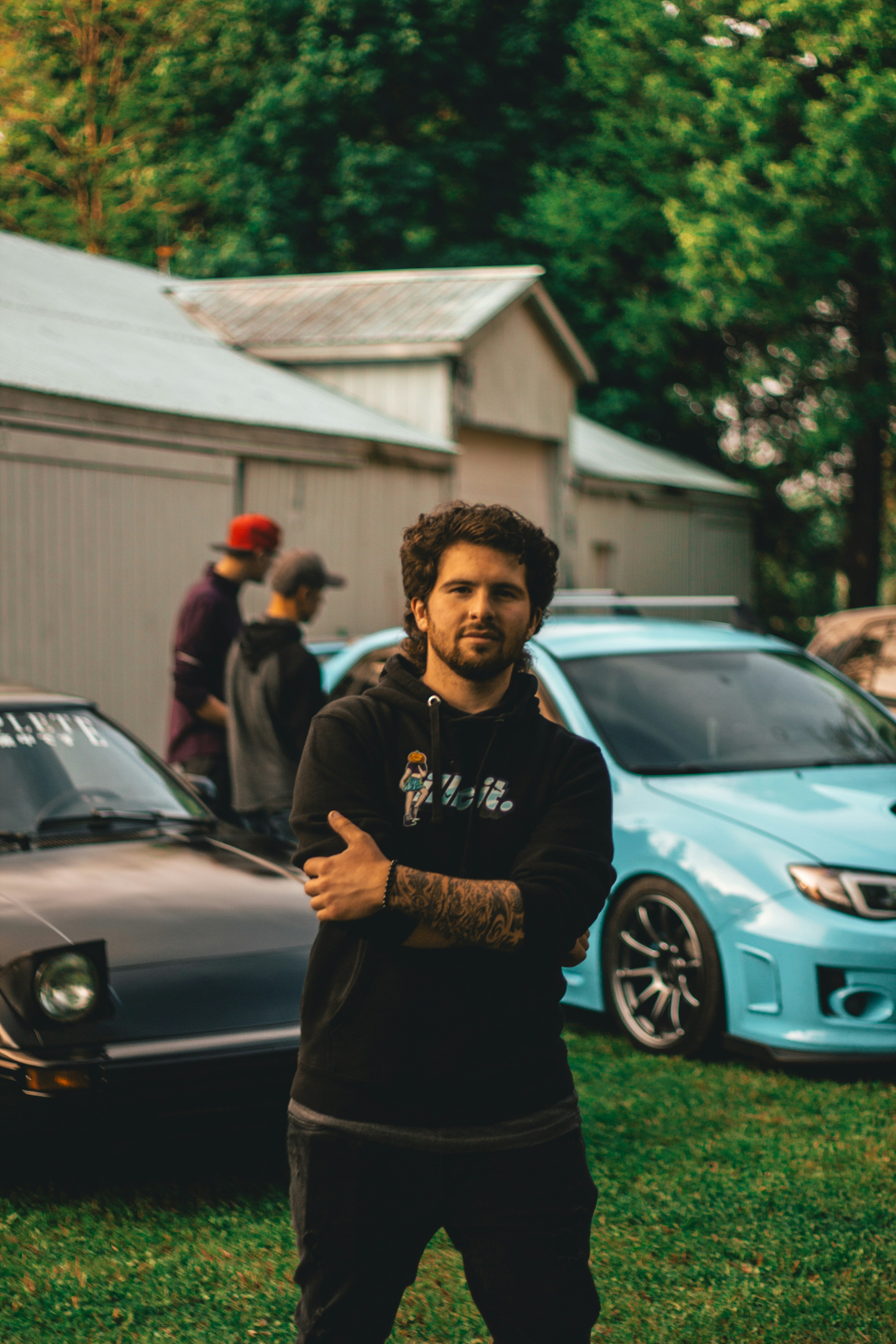 Portrait of Confidence: A Man in a Hoodie Between Classic and Modern Cars