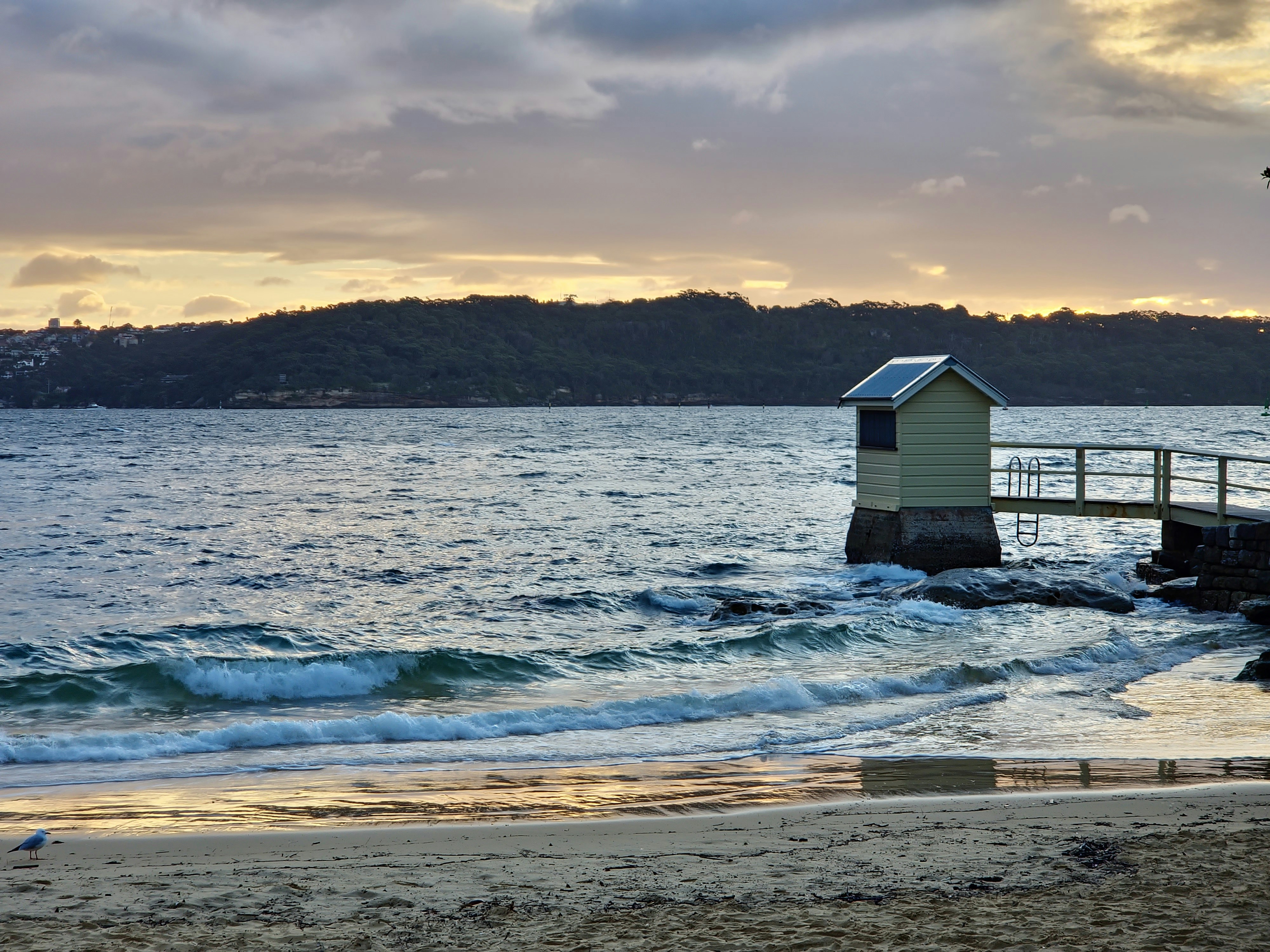 A small building sitting on top of a beach next to the ocean photo ...