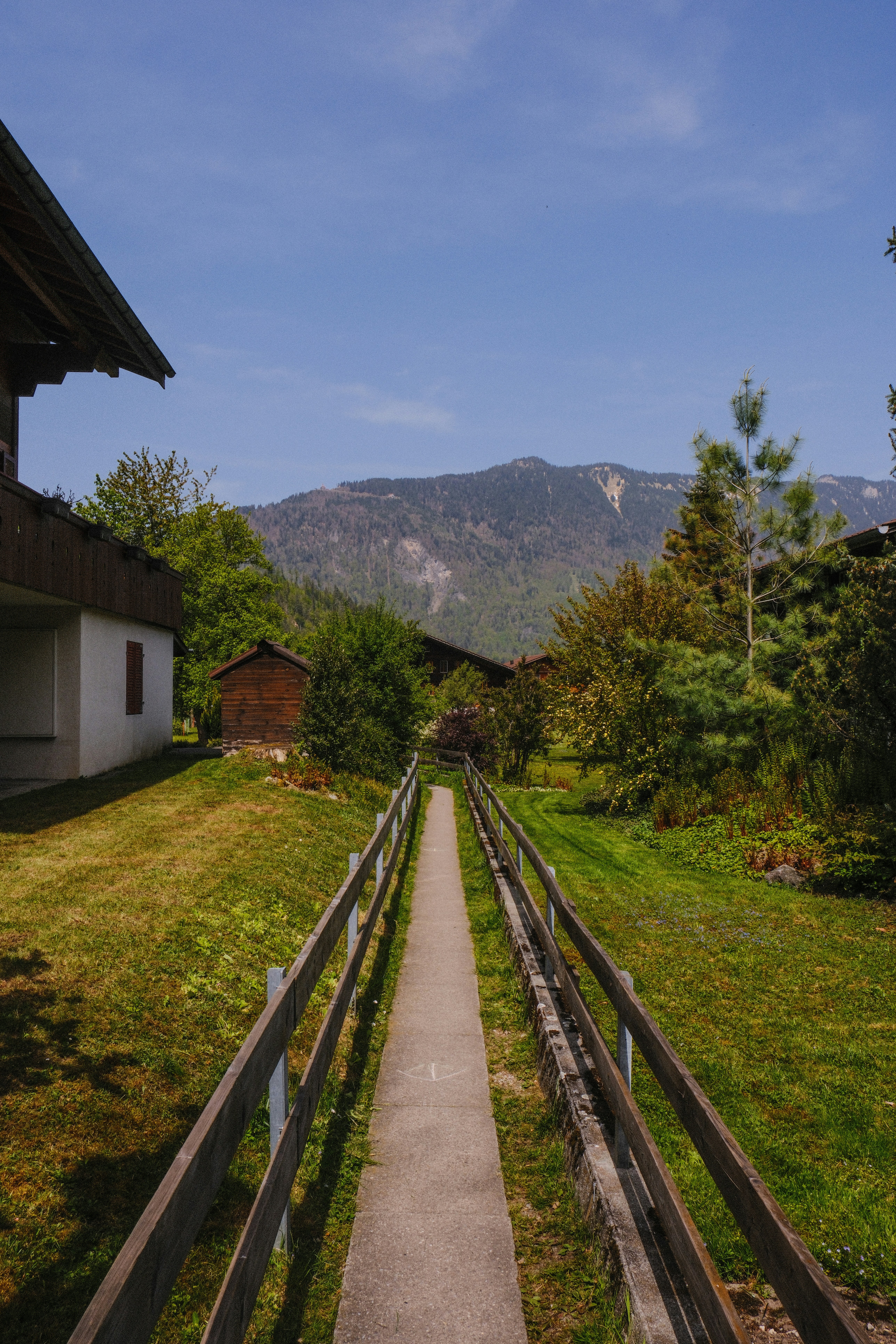 Sunlit Footpath to Distant Peaks: An Alpine Village Scene