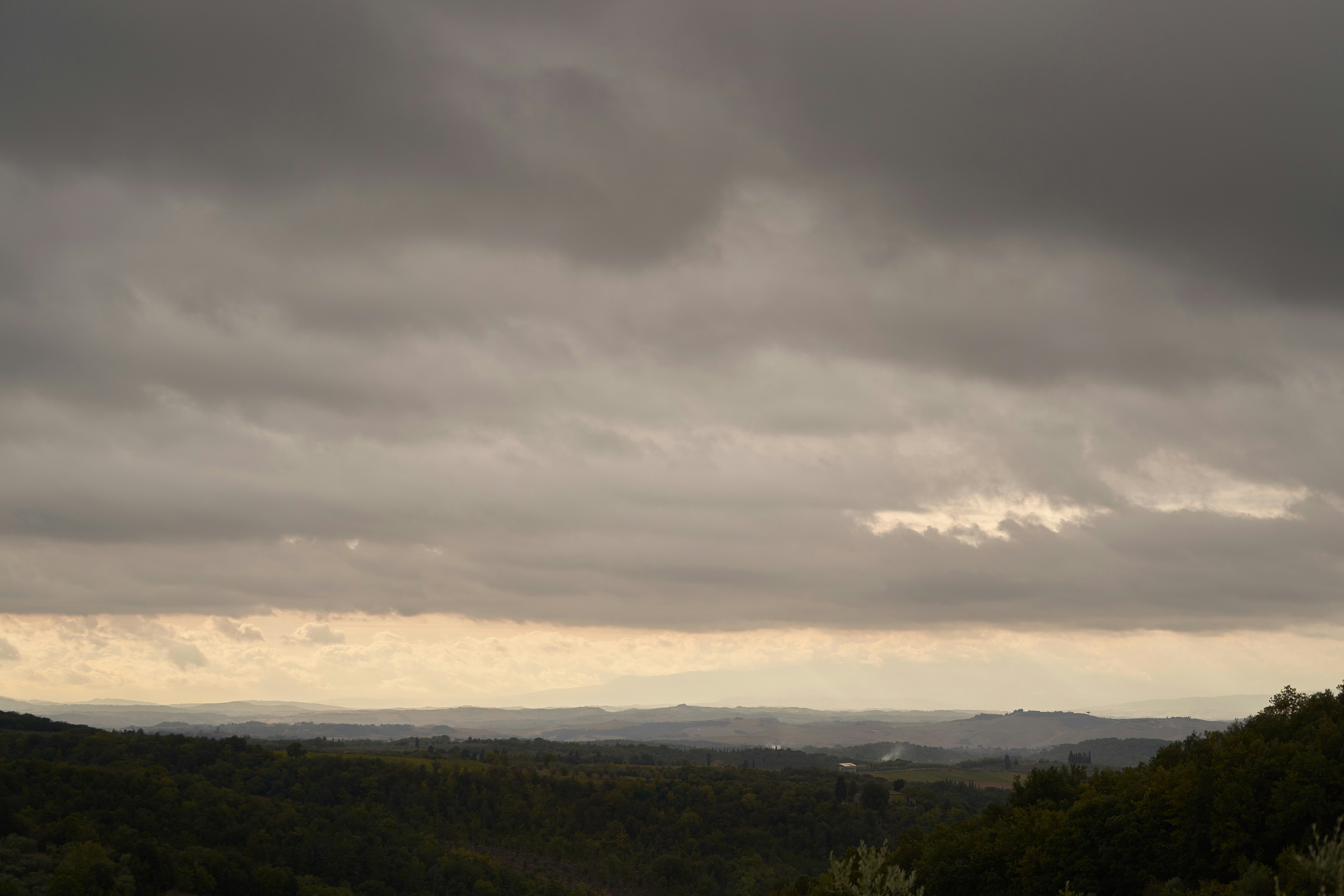 A cloudy sky over a valley with trees photo – Free Brown Image on Unsplash