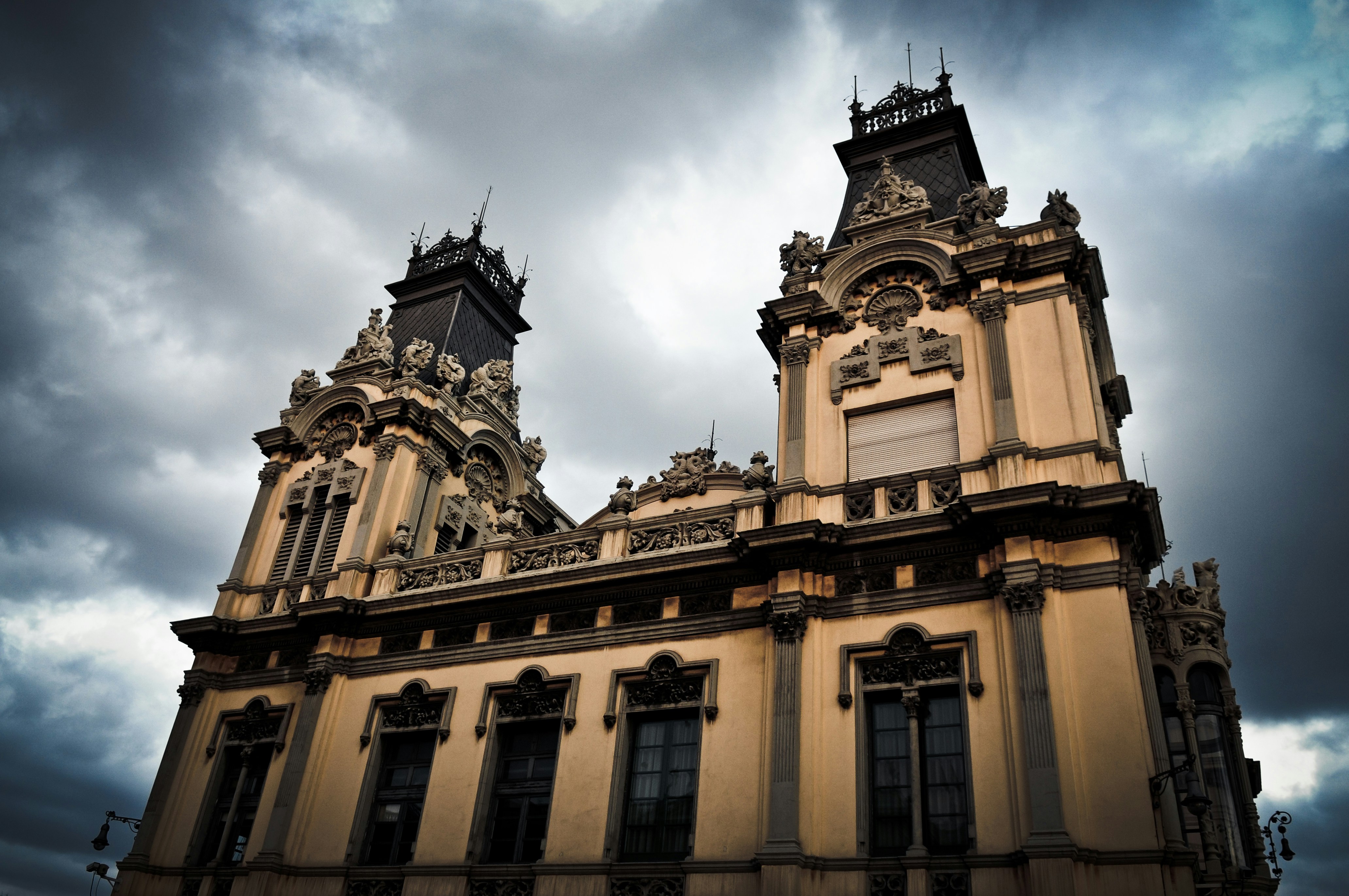 Ornate historical building with intricate carvings and tall towers against a dark, cloudy sky.