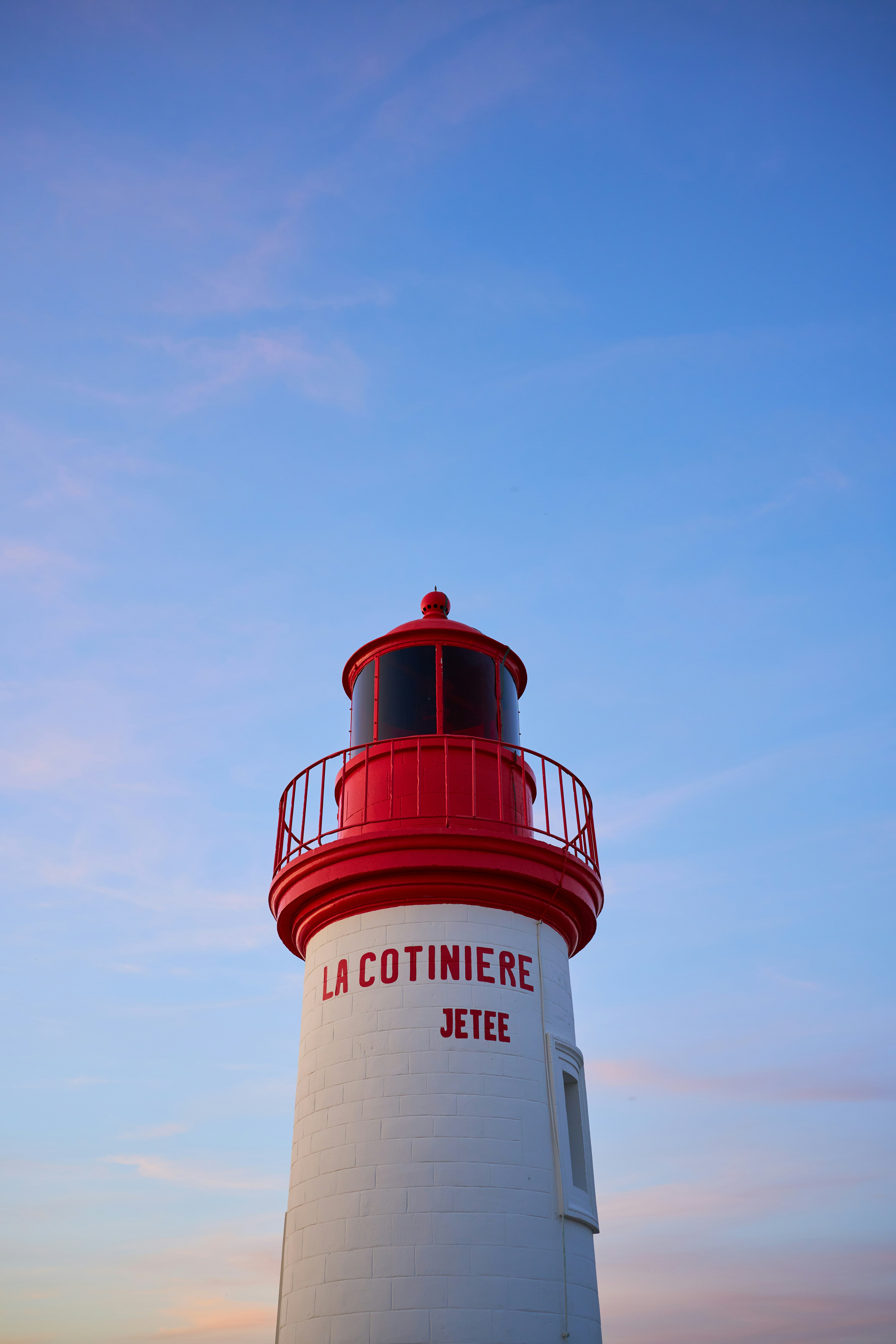 Crimson Lantern Against a Pale Blue Sky: La Cotinière Lighthouse Stands Tall