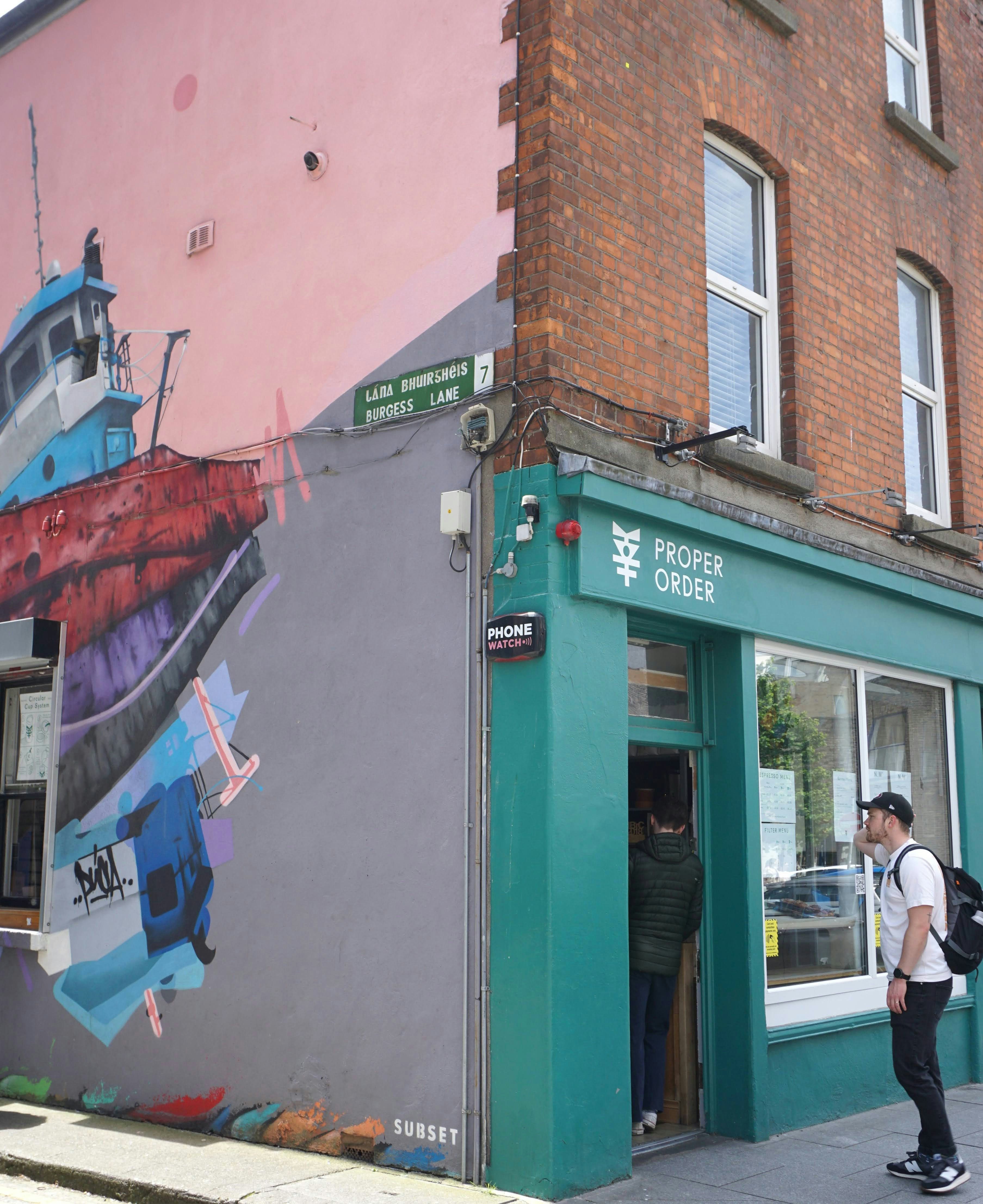 A man walking past a building with a mural on it photo – Free Dublin ...